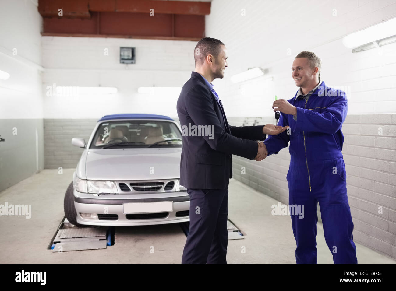 Mechanic giving car key while shaking hand to a client Stock Photo - Alamy