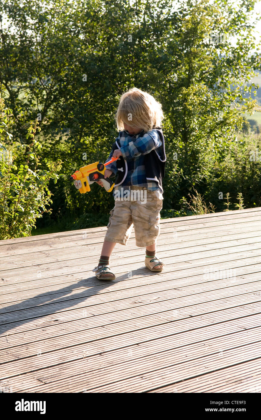 Little boy playing with a toy gun outside Stock Photo - Alamy