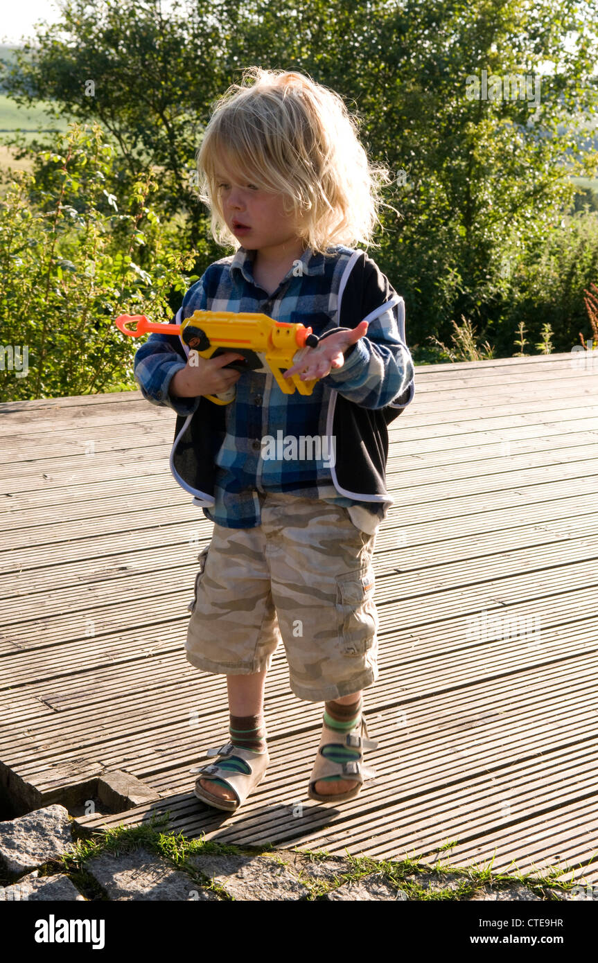 Little boy playing with a toy gun outside Stock Photo - Alamy