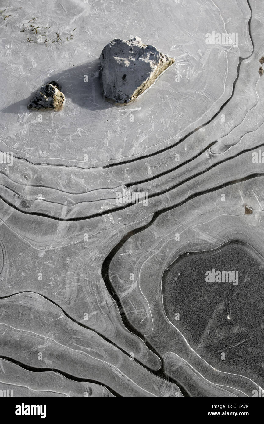 Stones encased in ice, and patterns of ice crystals on a pool of water ...