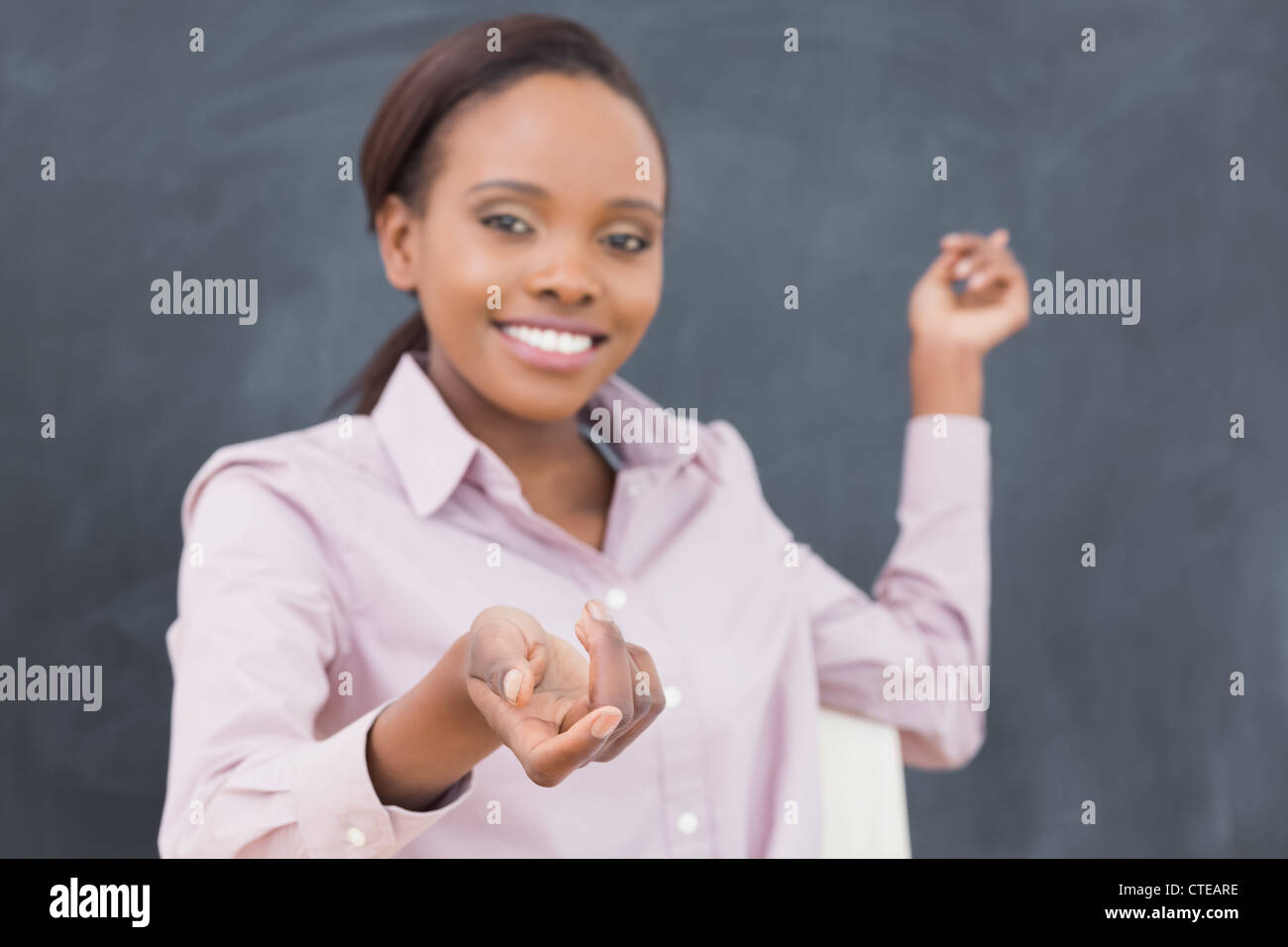 Black teacher showing the blackboard while smiling Stock Photo - Alamy