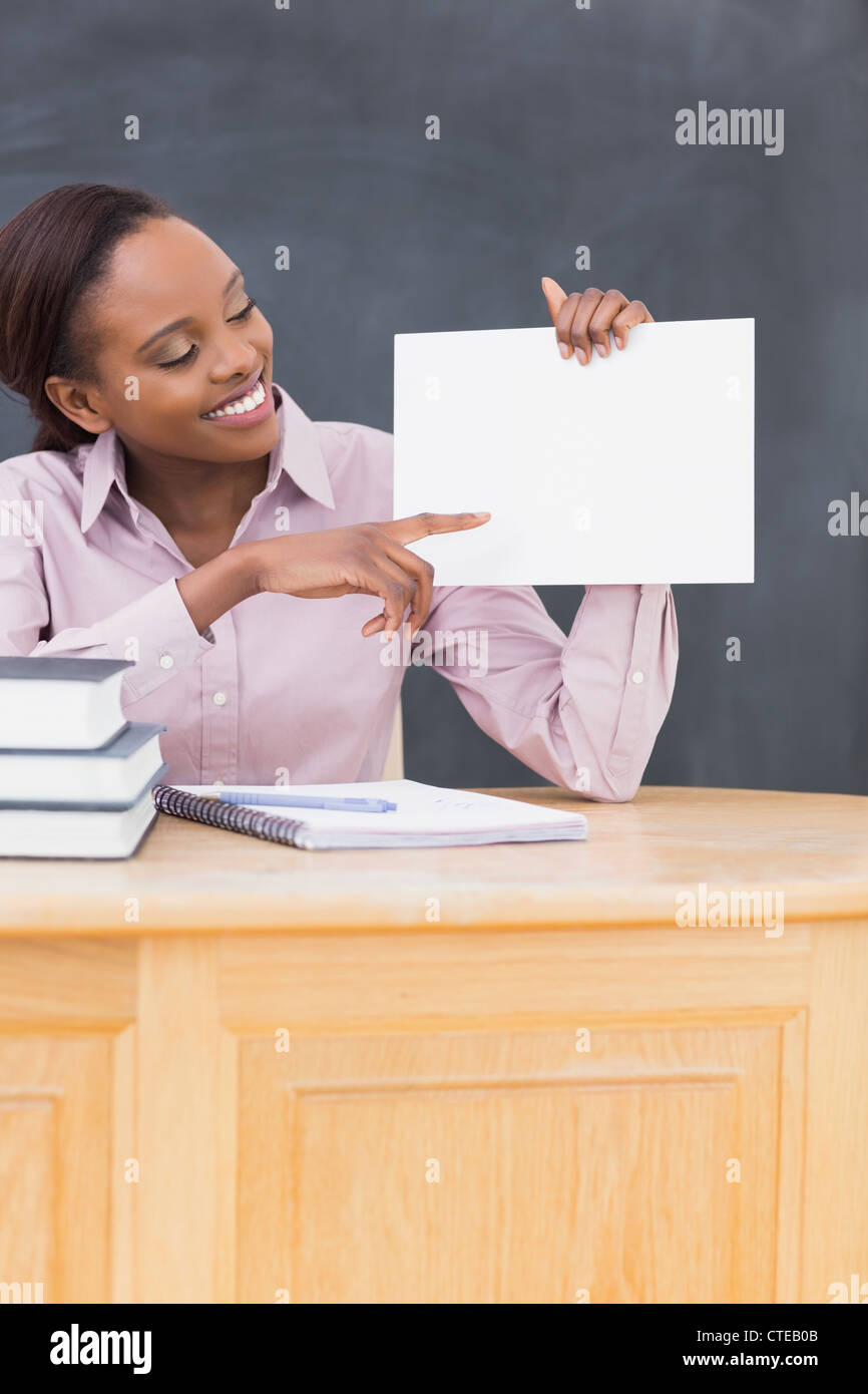 Black teacher holding a blank paper at desk Stock Photo - Alamy