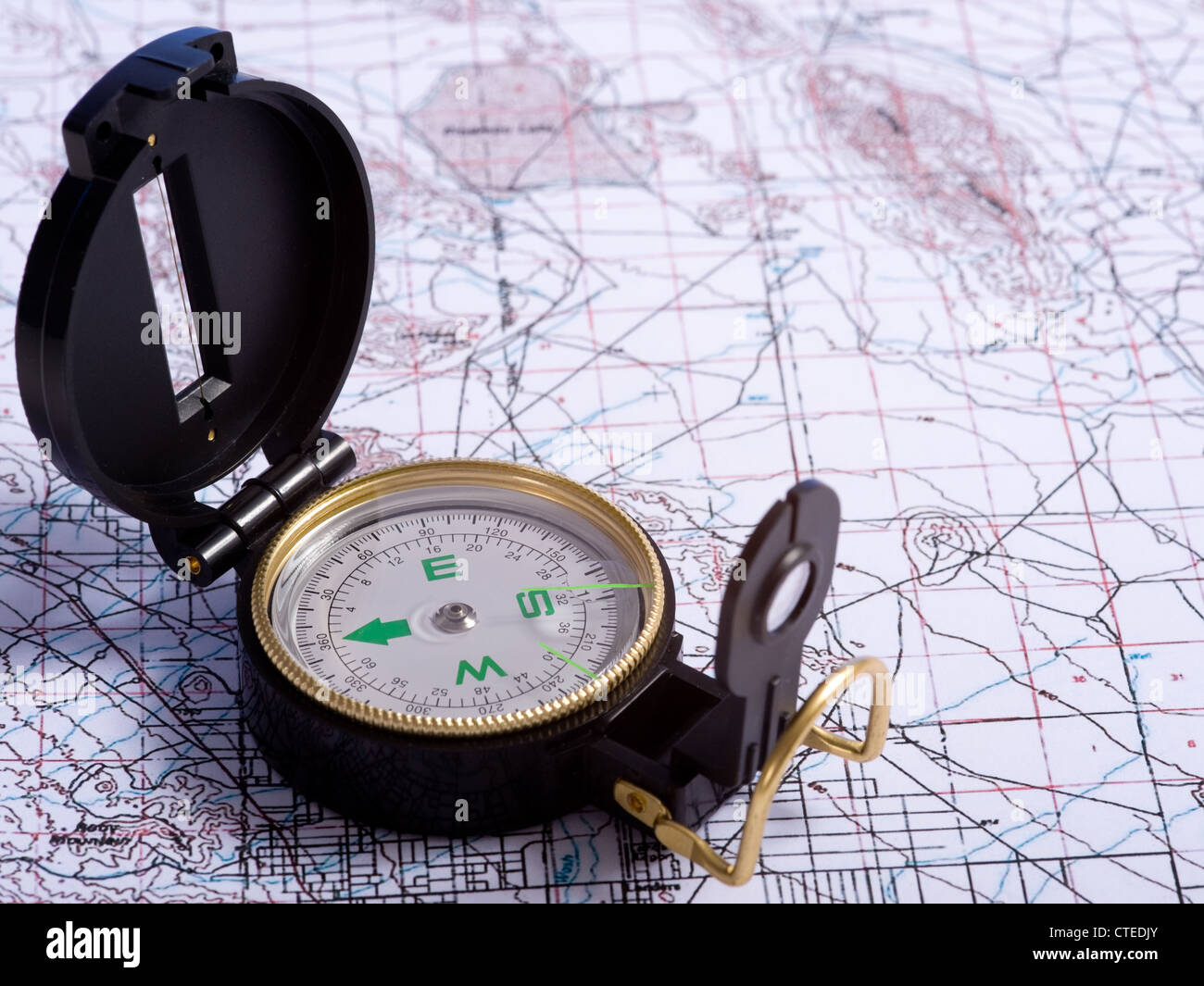 A black engineer's compass lying on top of a topographical map Stock ...