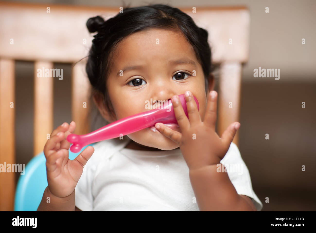 hispanic baby girl learning to hold a spoon by herself Stock Photo - Alamy