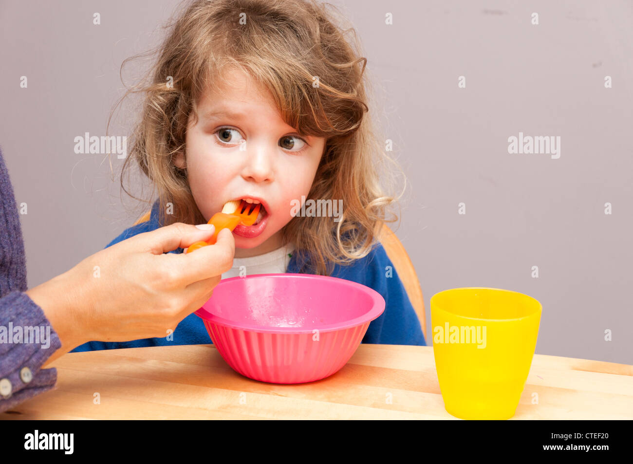 Mother helping young daughter, three years old, to eat her meal Stock ...