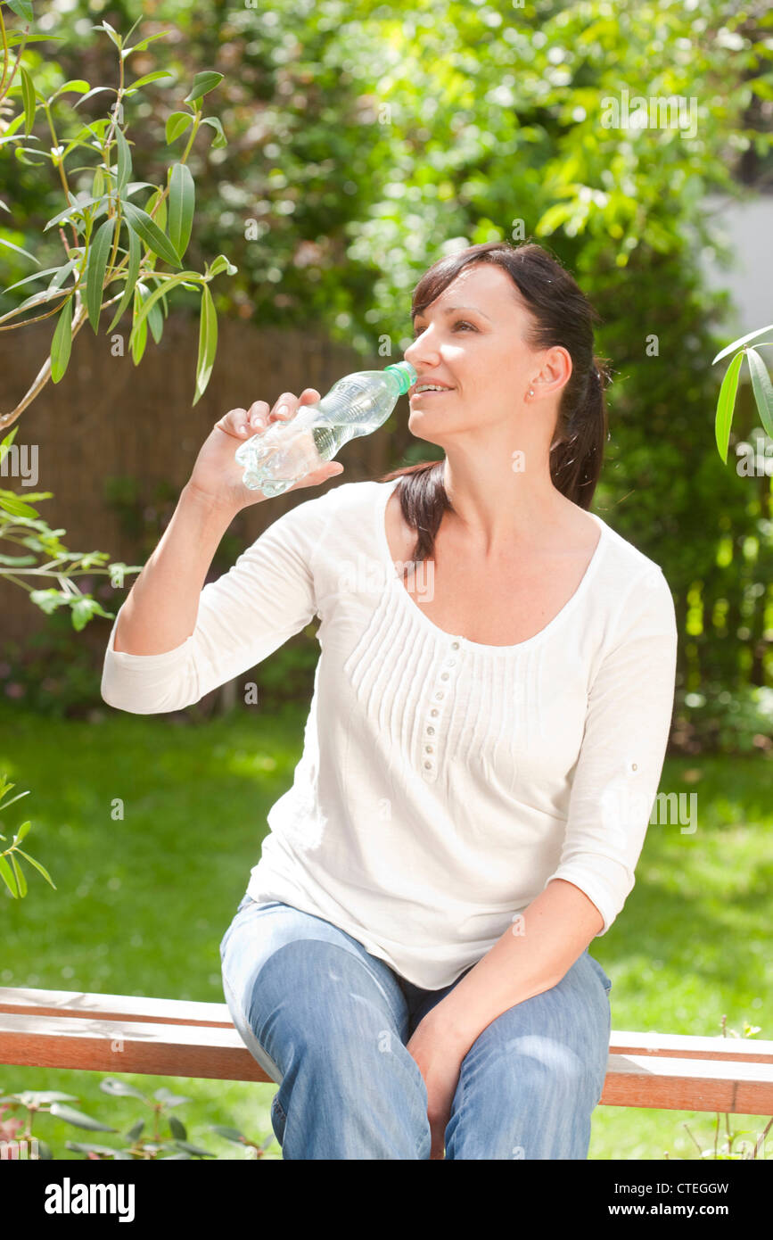 Woman drinking mineral water in garden Stock Photo - Alamy
