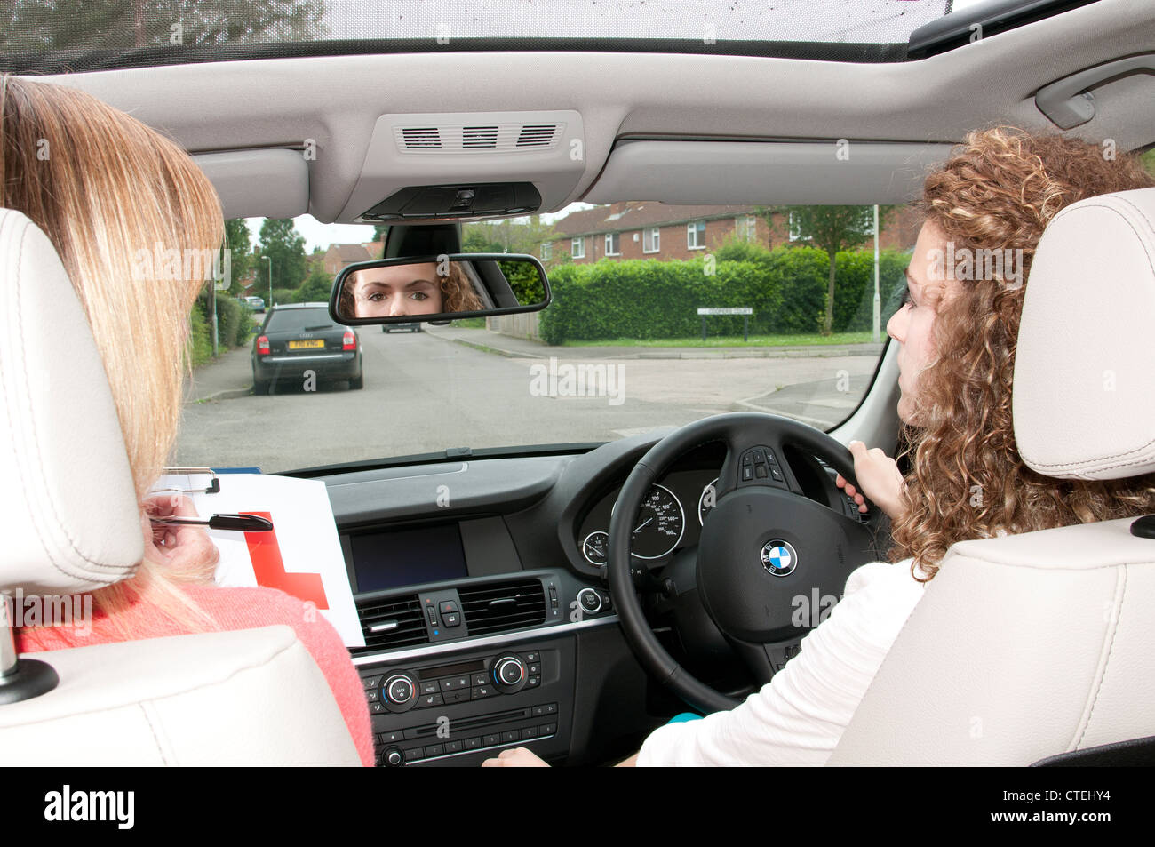 Teenage girl holding L learner plate with instructor passes driving ...