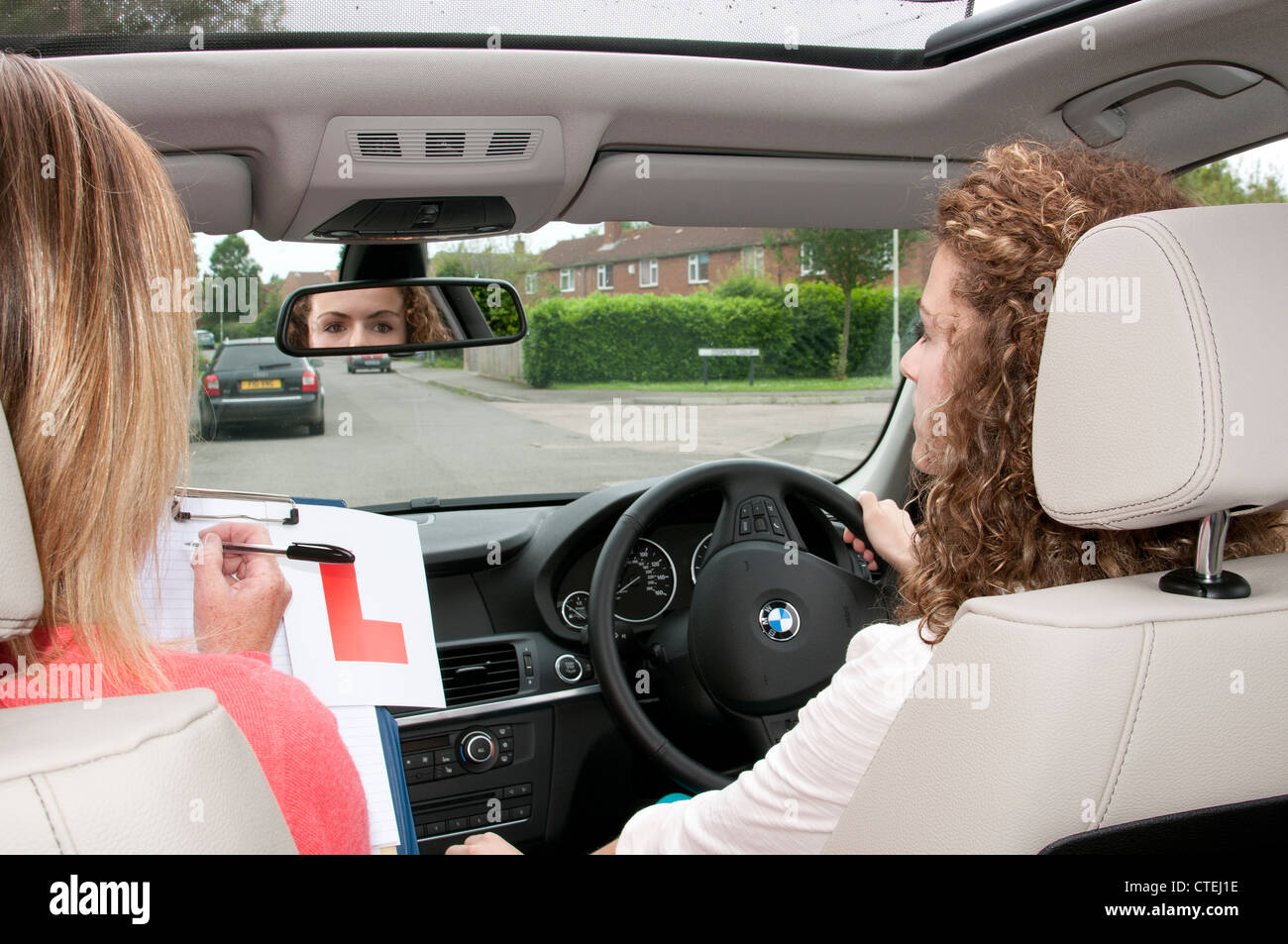 Teenage girl holding L learner plate with instructor passes driving ...