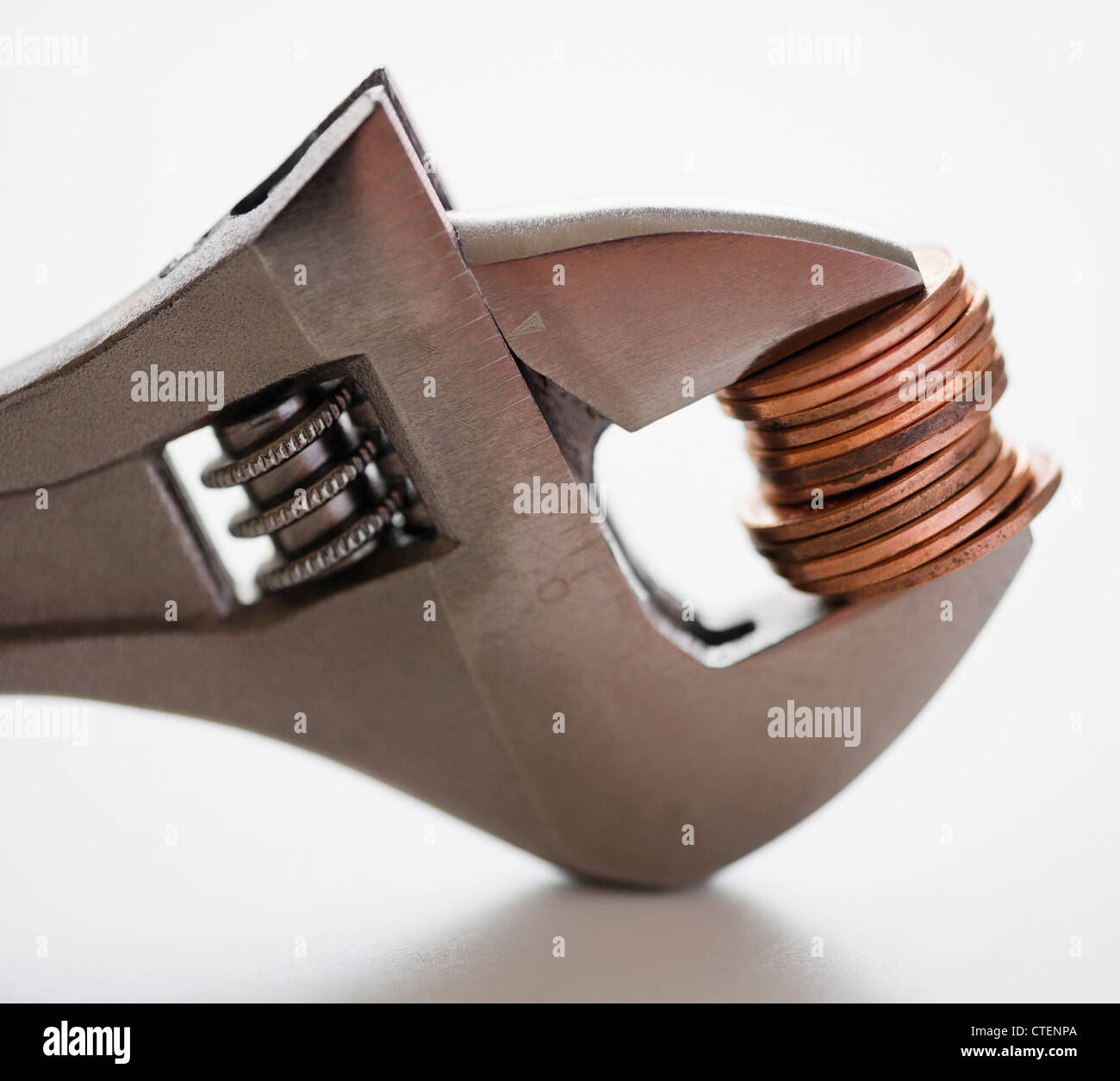 Wrench squeezing coins Stock Photo - Alamy