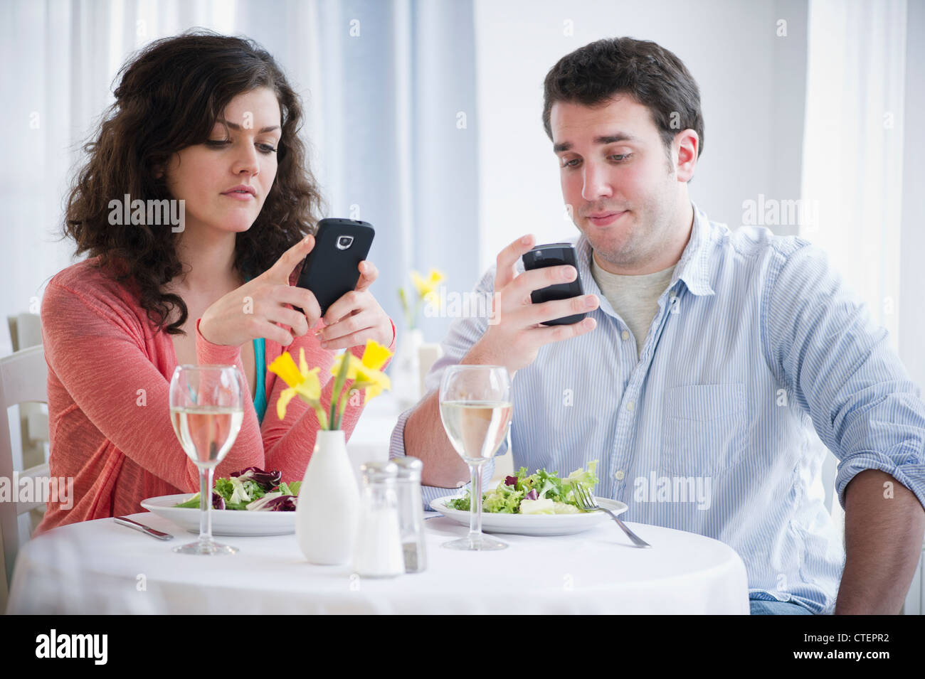 USA, New Jersey, Jersey City, Couple having dinner and text messaging ...