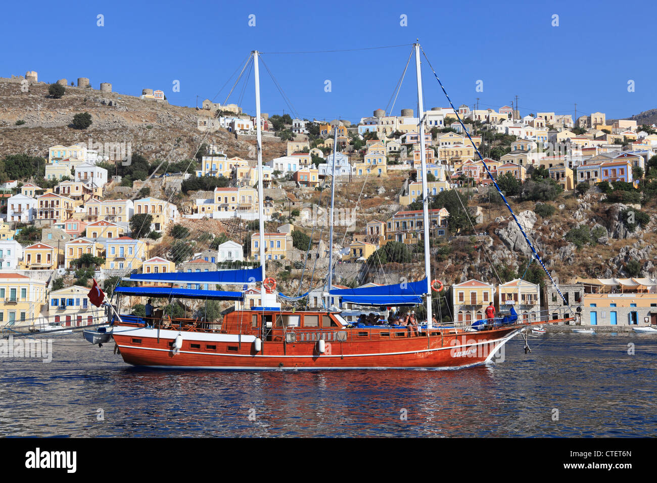 A gulet boat sails into Symi harbour on the Greek island of Symi in the ...