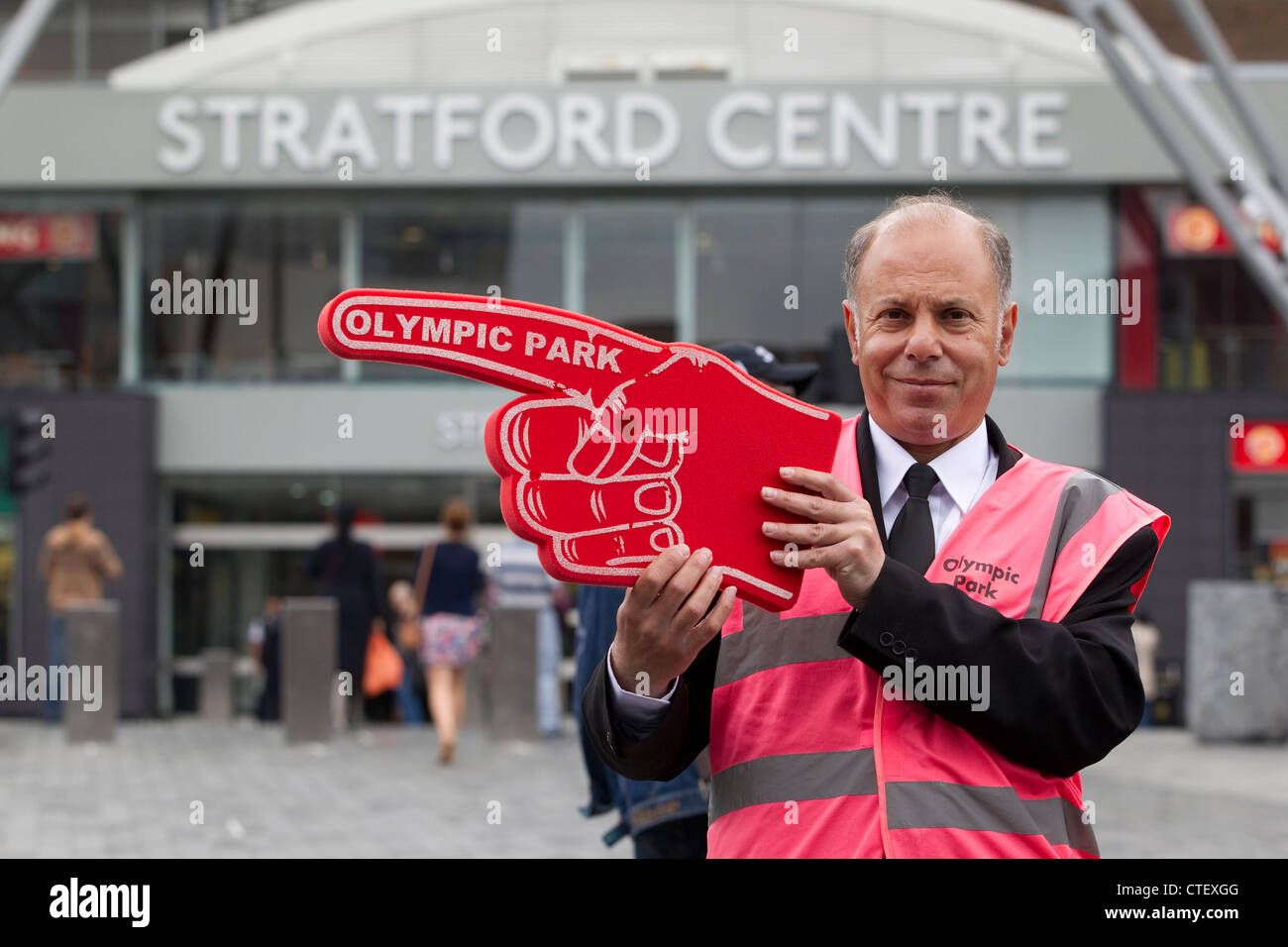 Olympic volunteer holding Olympic Park sign outside the Stratford ...