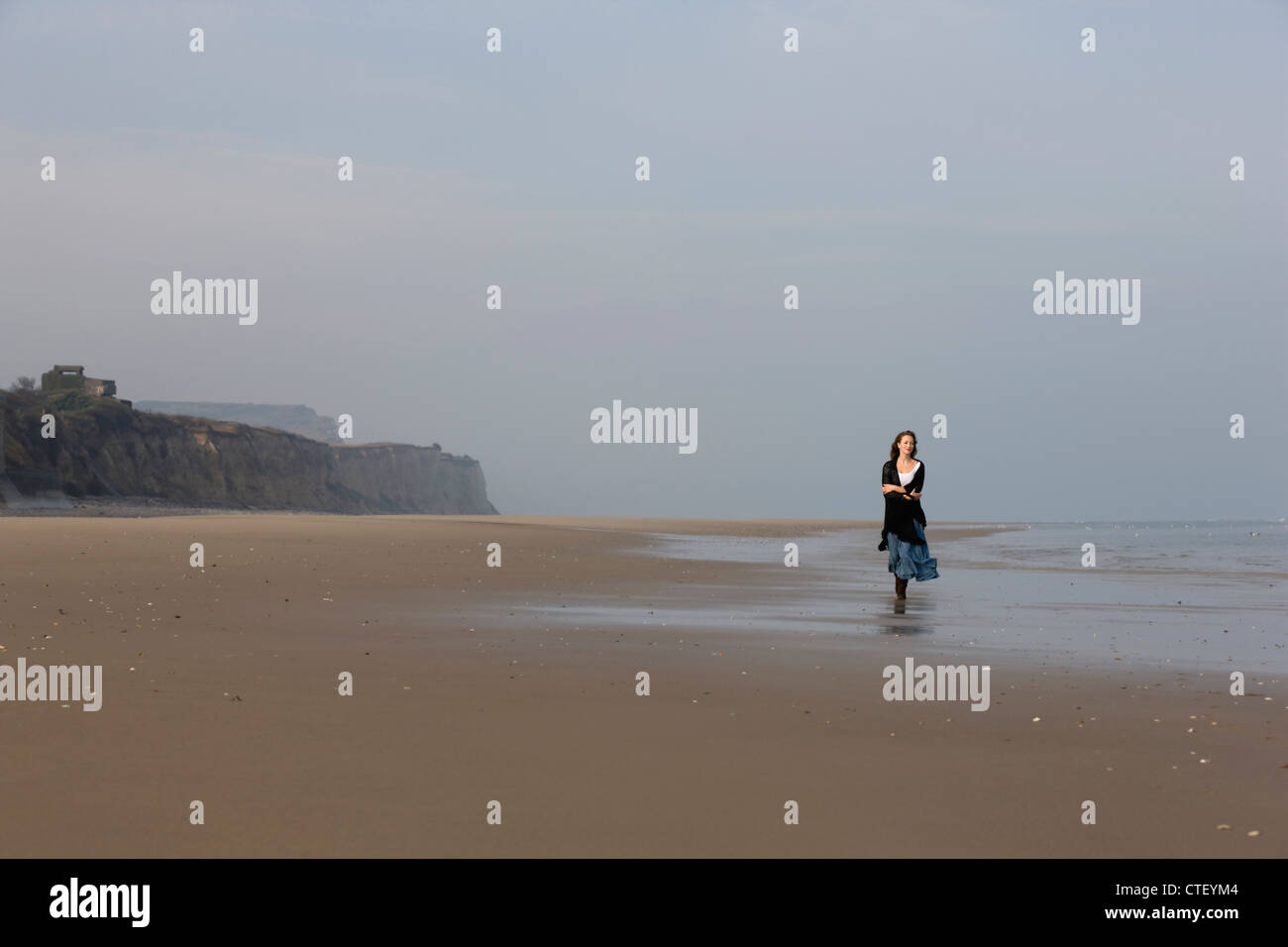 France, Pas-de-Calais, Escalles, Young woman strolling on empty beach ...