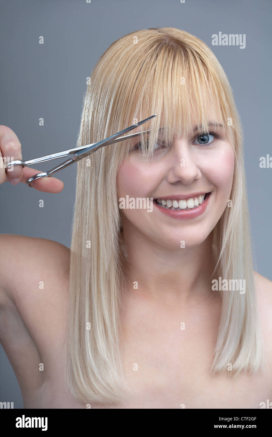 Woman cutting bangs, studio shot Stock Photo - Alamy