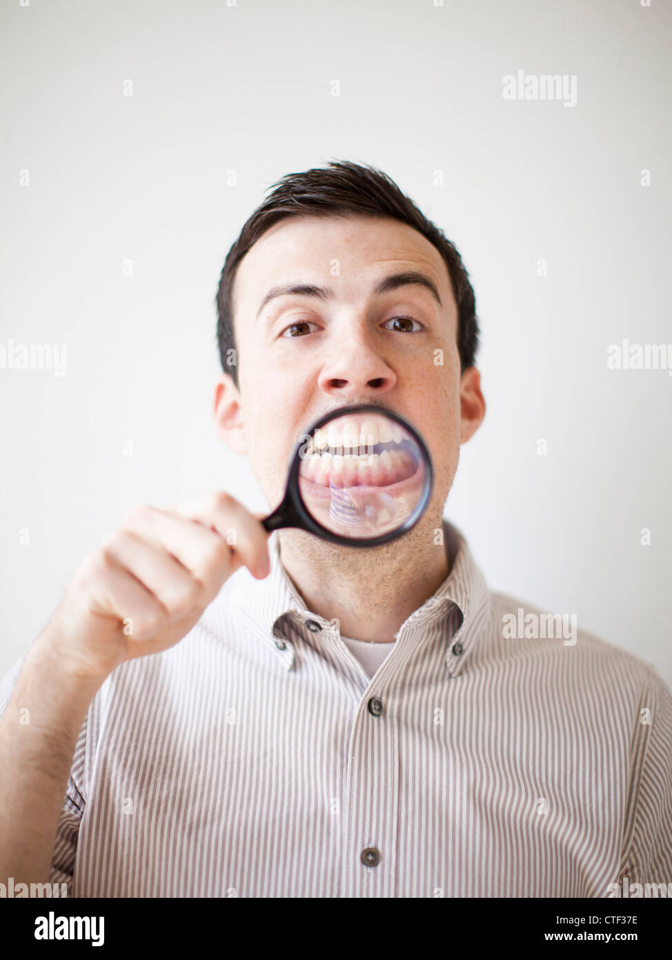 Man looking standing looking through magnifying glass Stock Photo - Alamy