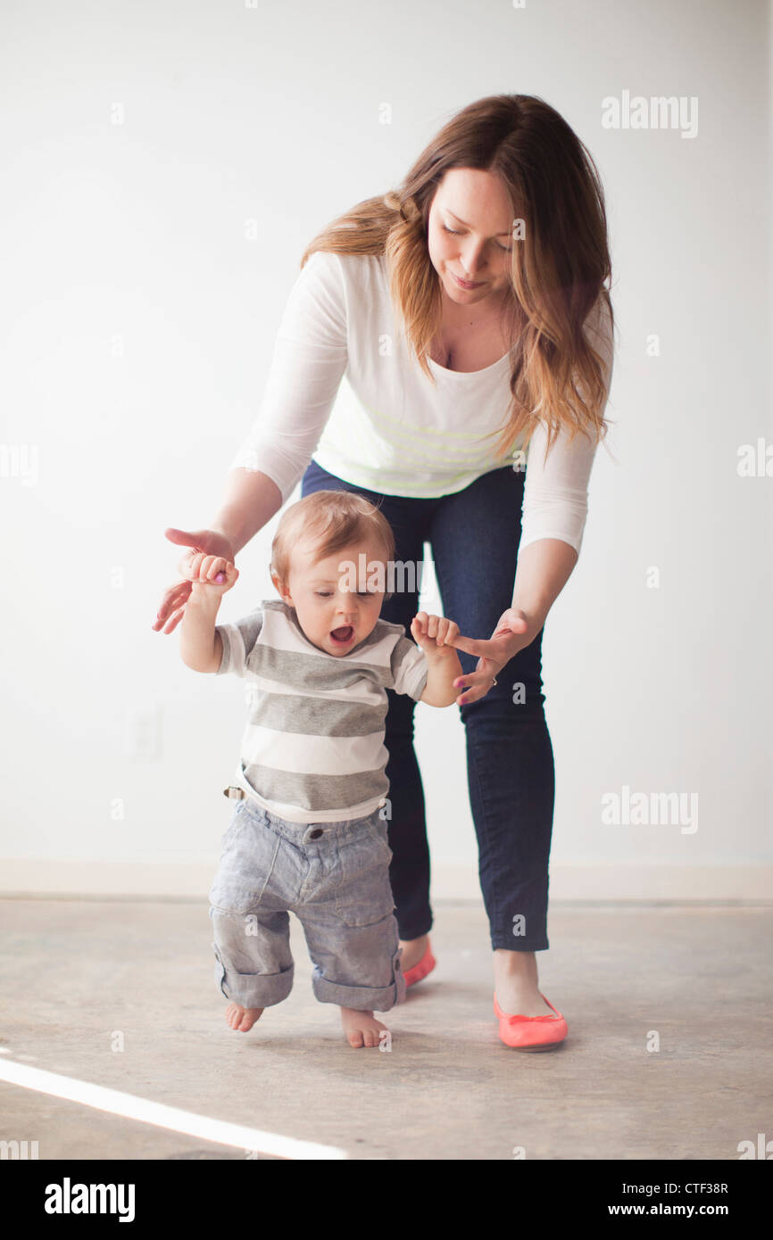 USA, Utah, Salt Lake City, Young mother assisting baby boy (6-11 months ...