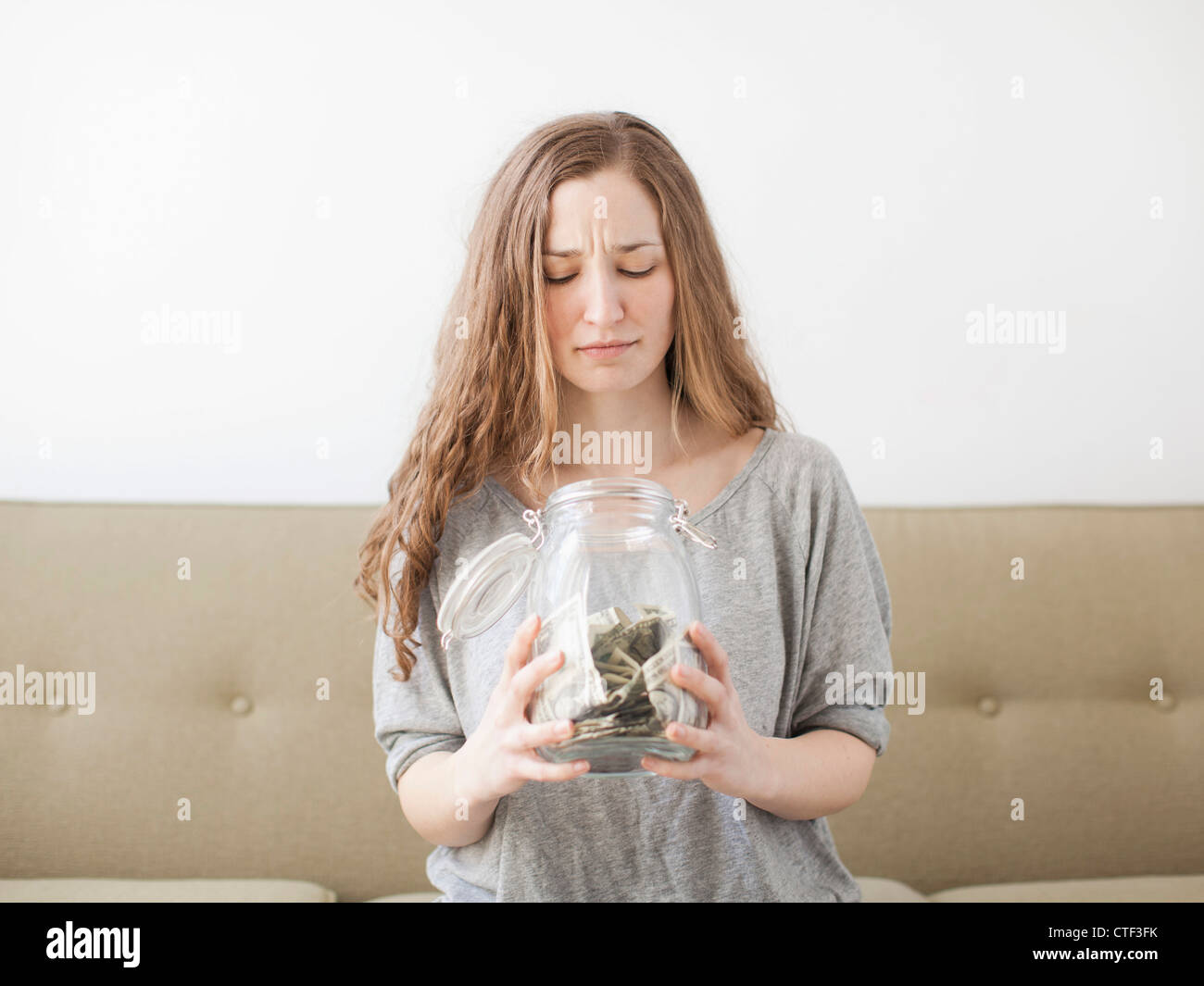 USA, Utah, Salt Lake City, Young woman looking into savings jar with ...