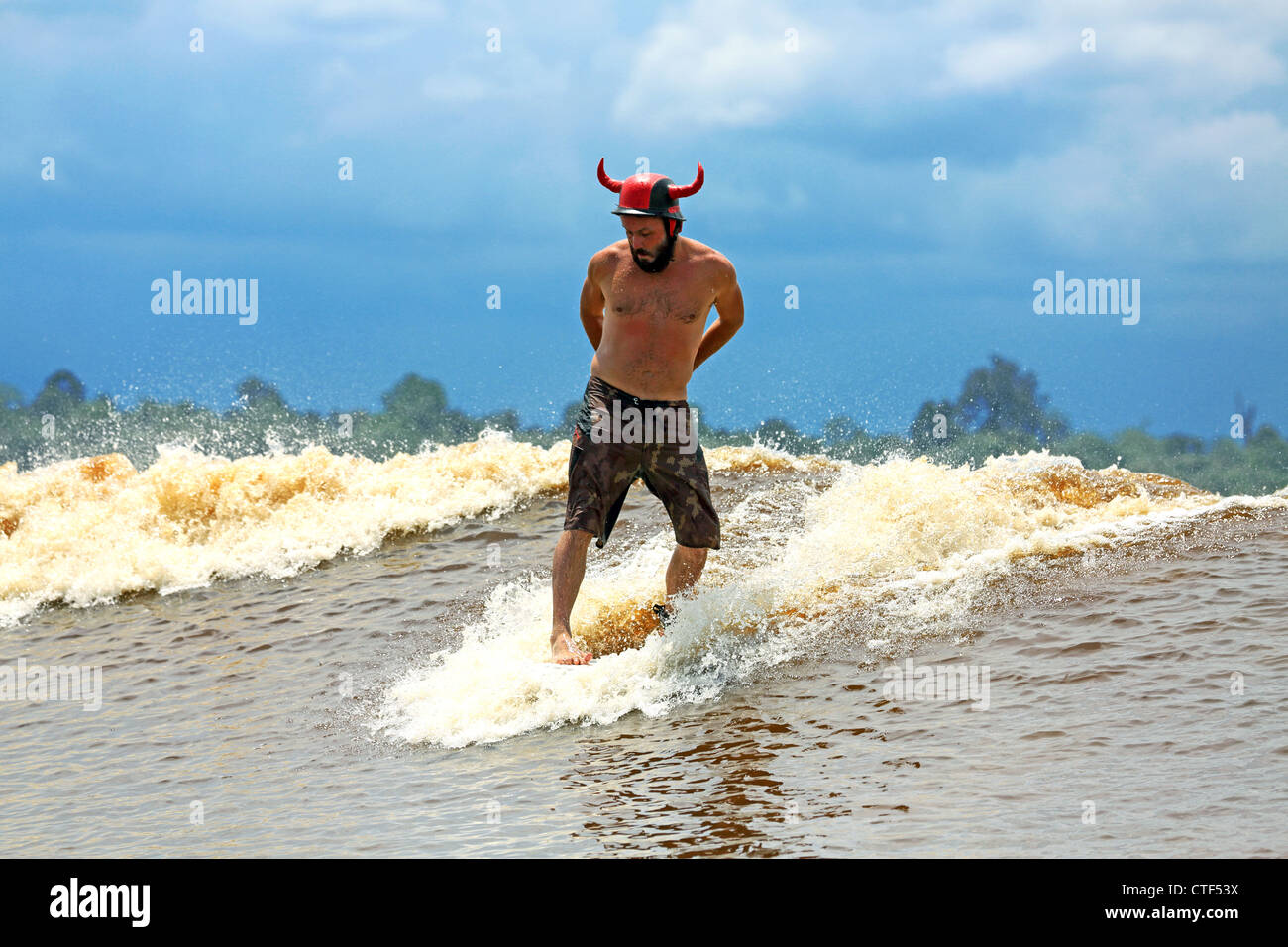 Man river surfing a tidal bore wave on the Kampar River, known locally ...