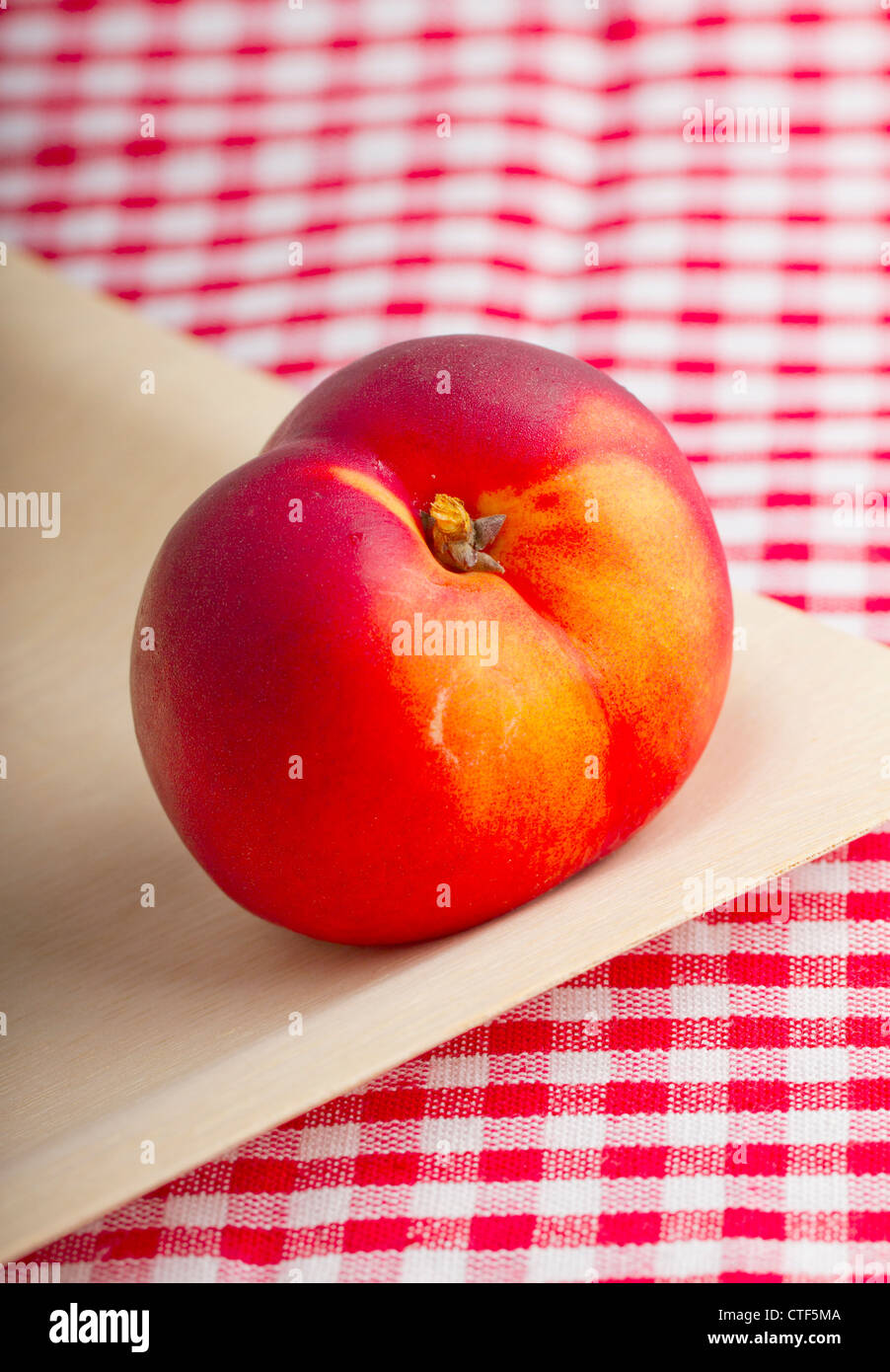 Single red peach over a wooden plate Stock Photo - Alamy