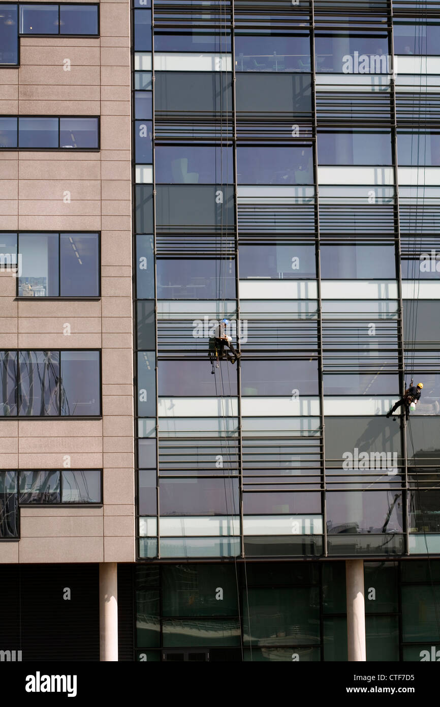 Window cleaners abseiling down the front of one of the office buildings ...