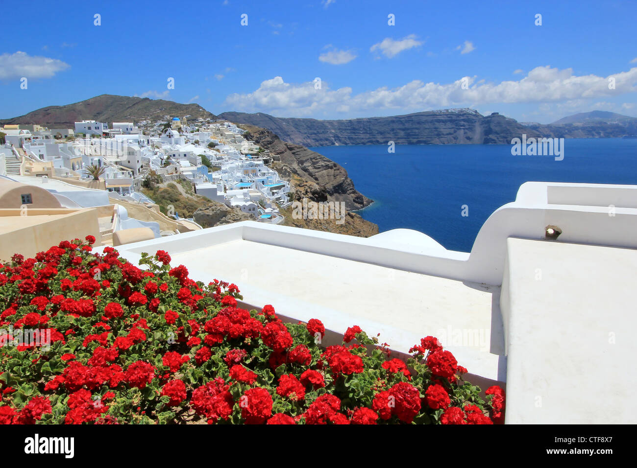 View on the caldera behind red flowers at Oia, Santorini, Greece, by ...