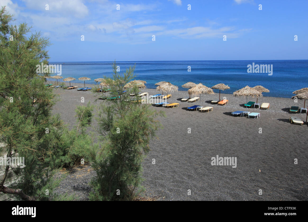 Black beach with umbrellas made of straw and colorful deckchairs at ...