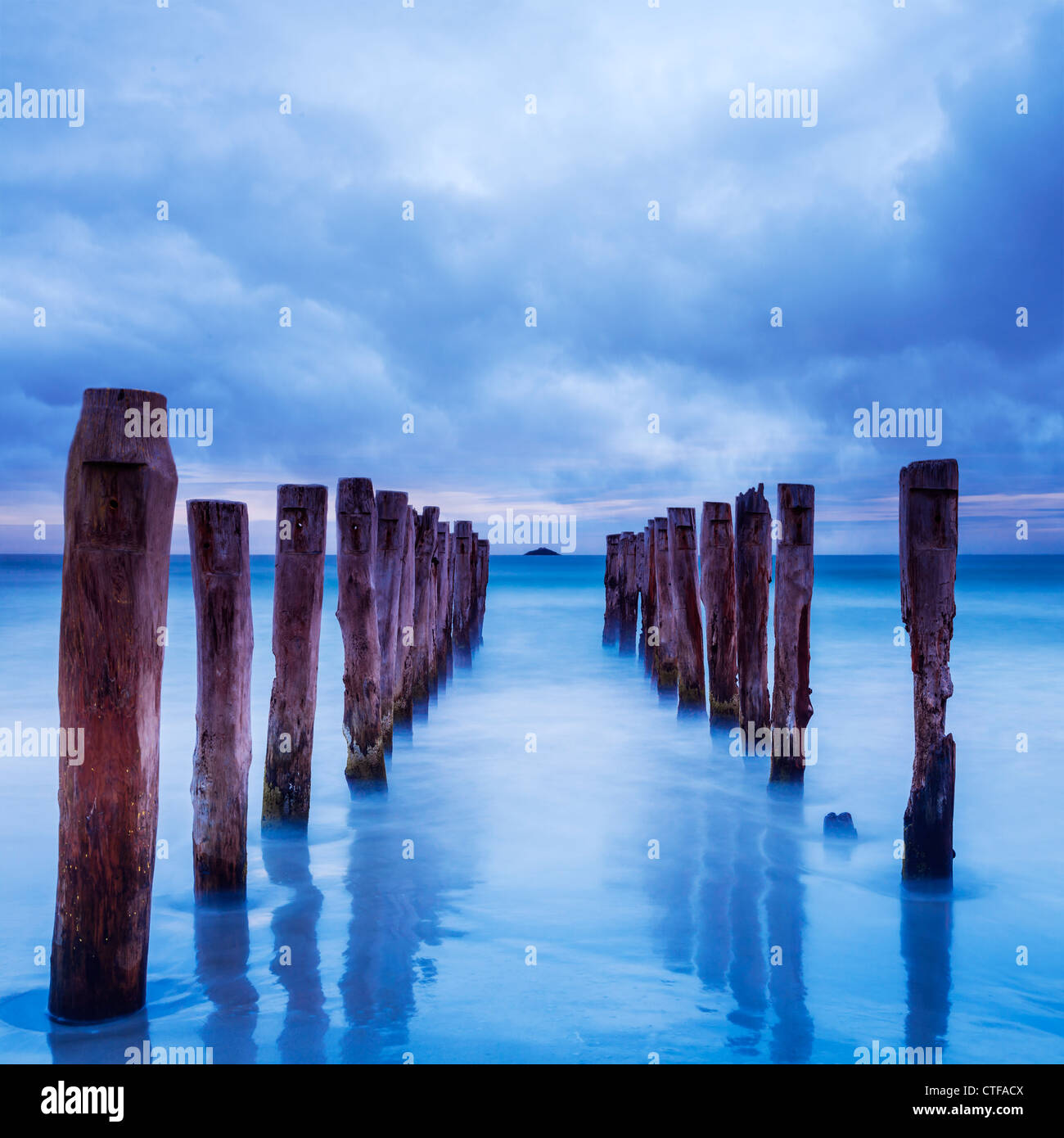 Storm clouds gather over old jetty posts Stock Photo - Alamy
