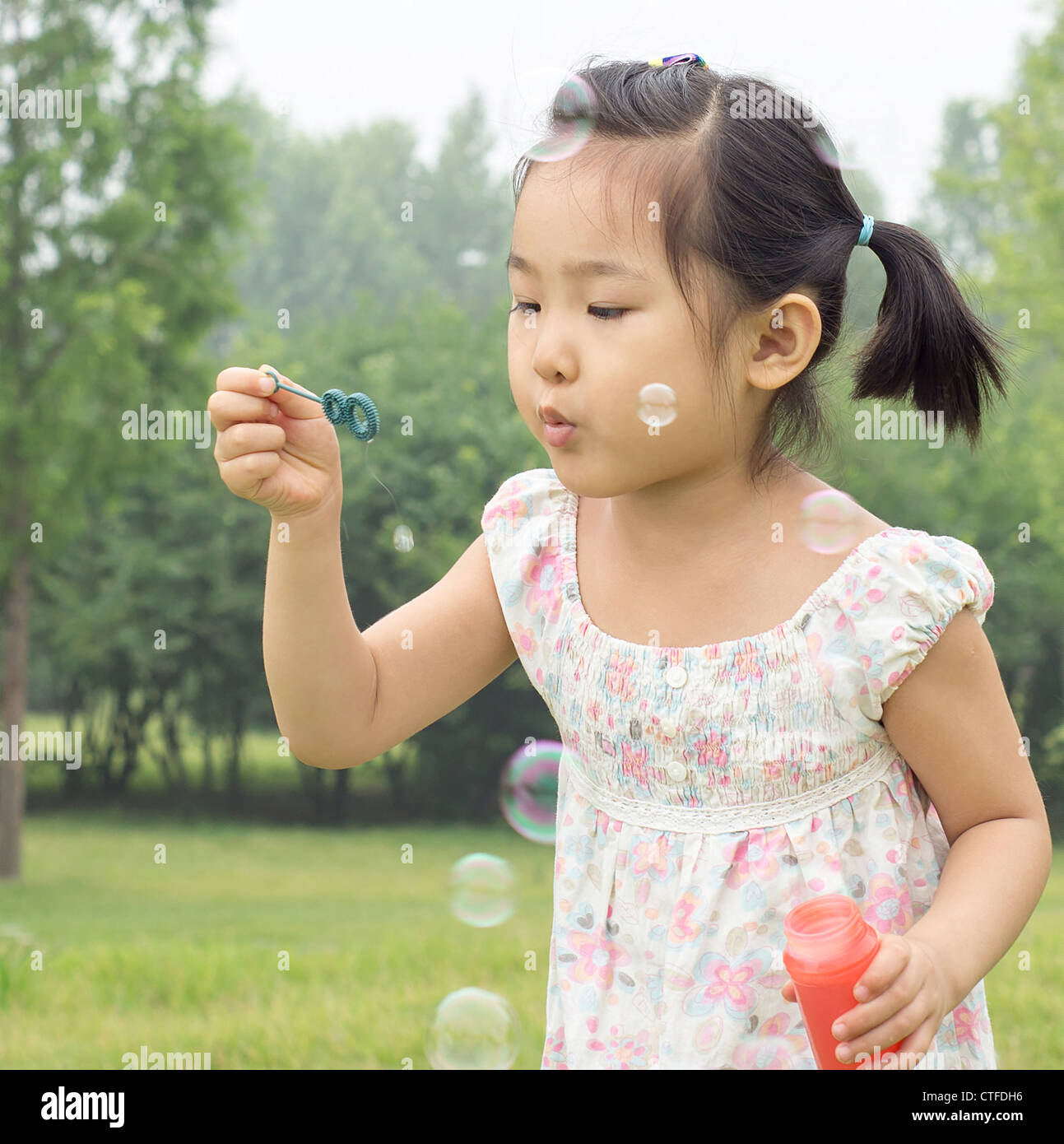 The little girl playing blowing bubbles game Stock Photo - Alamy