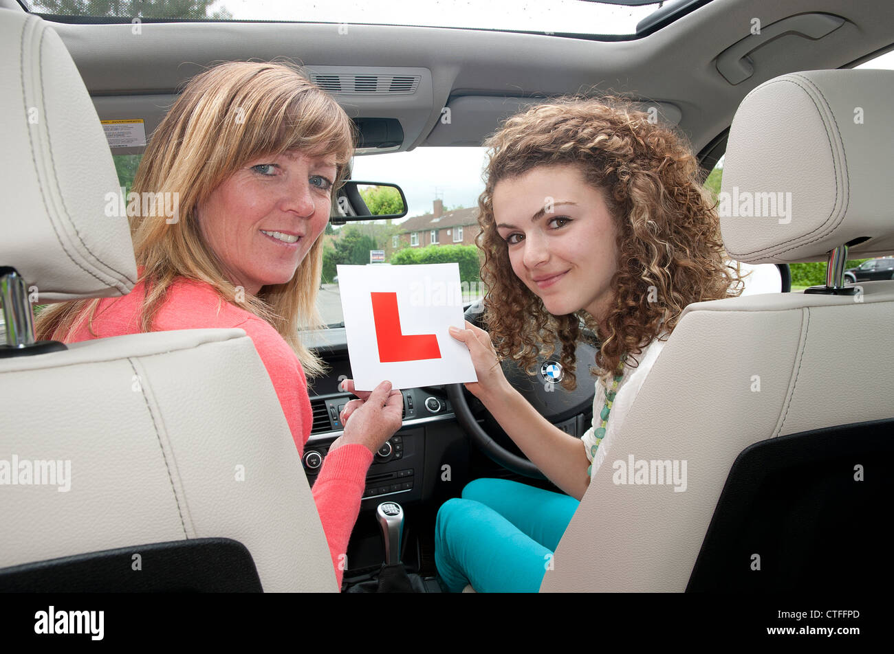 Teenage girl holding L learner plate with instructor passes driving ...