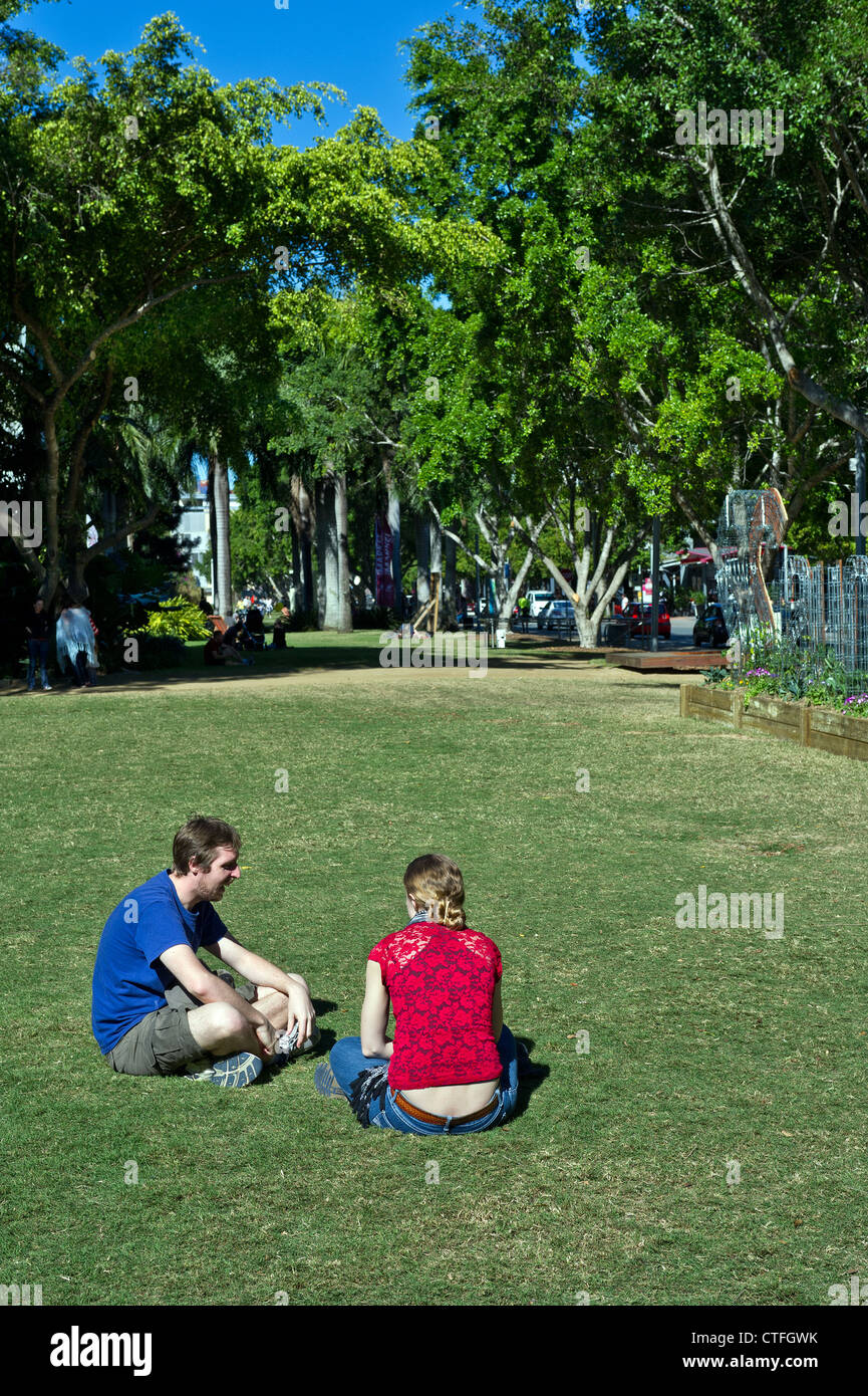 Two people sitting on grass on South Bank in Brisbane in Queensland ...