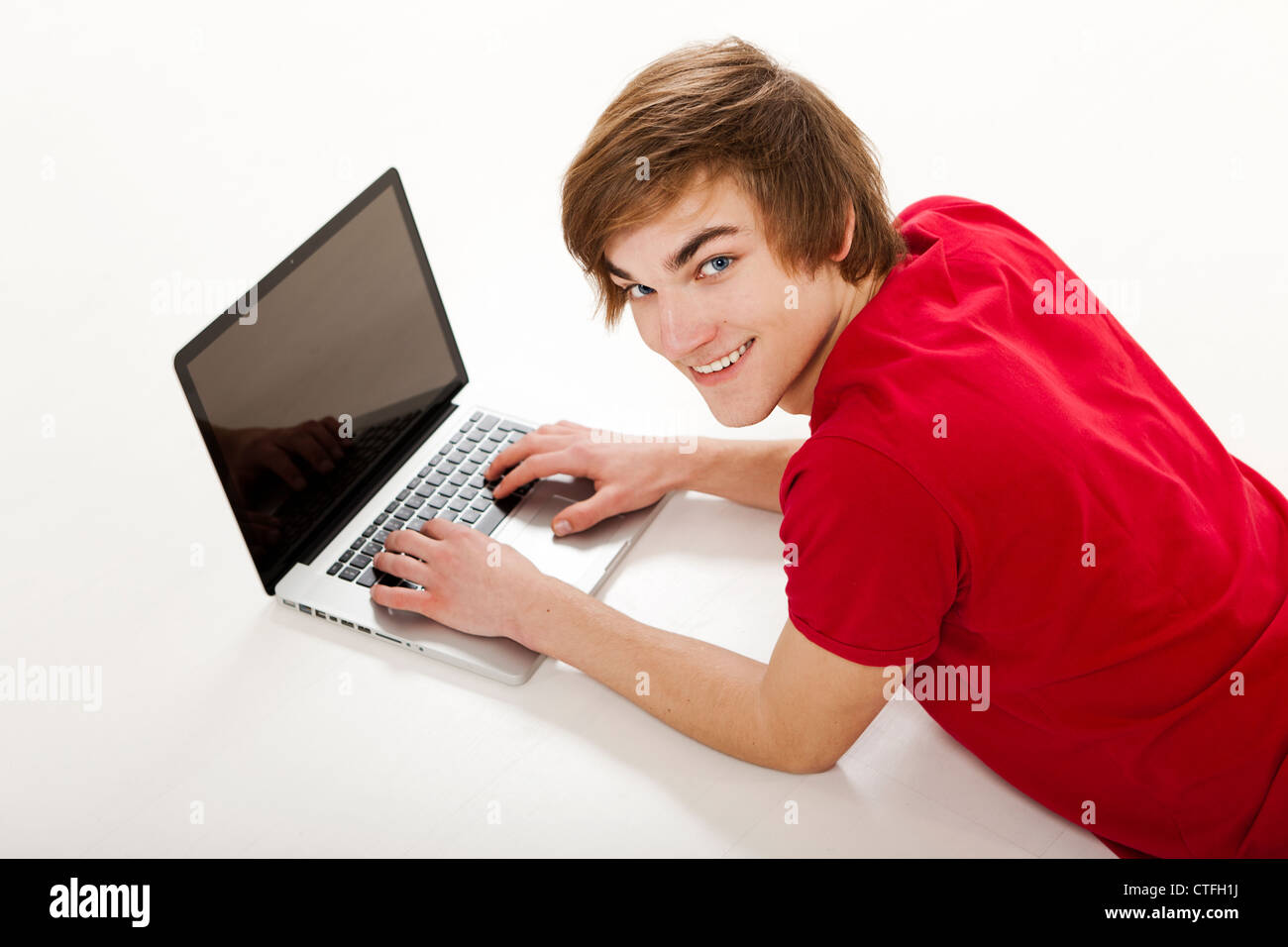 Young man lying in the floor and working with a laptop Stock Photo - Alamy