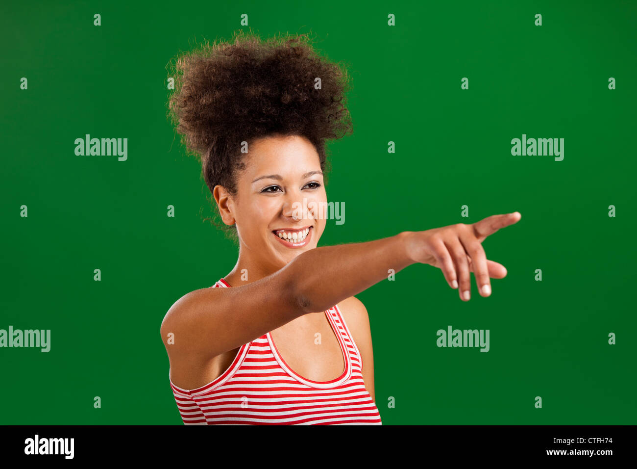 Happy African woman pointing to something over a green background Stock ...