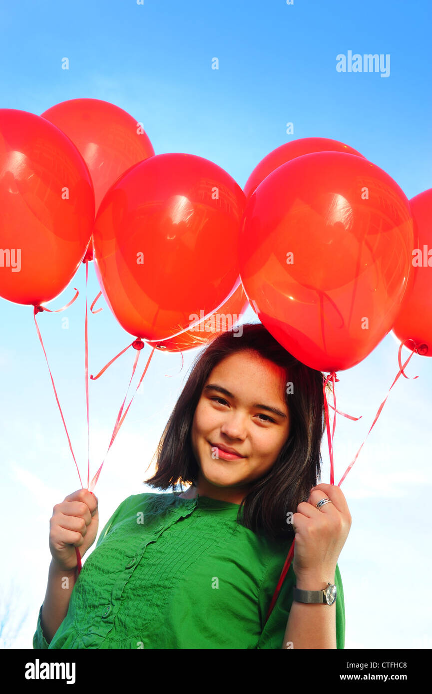 Asian American teenager girl happy holding red balloons Stock Photo - Alamy
