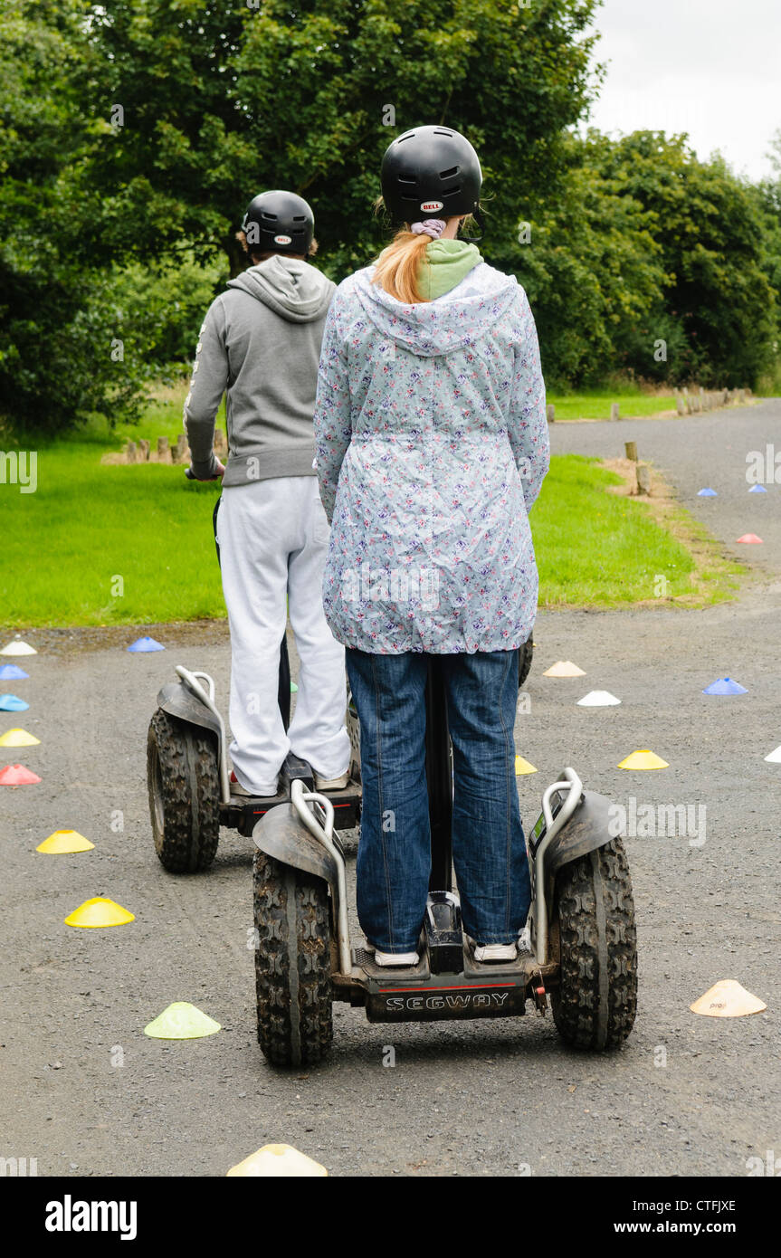 People riding Segway personal transportation around an obstacle course ...