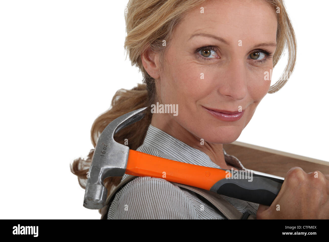 Blond woman holding hammer over shoulder Stock Photo - Alamy