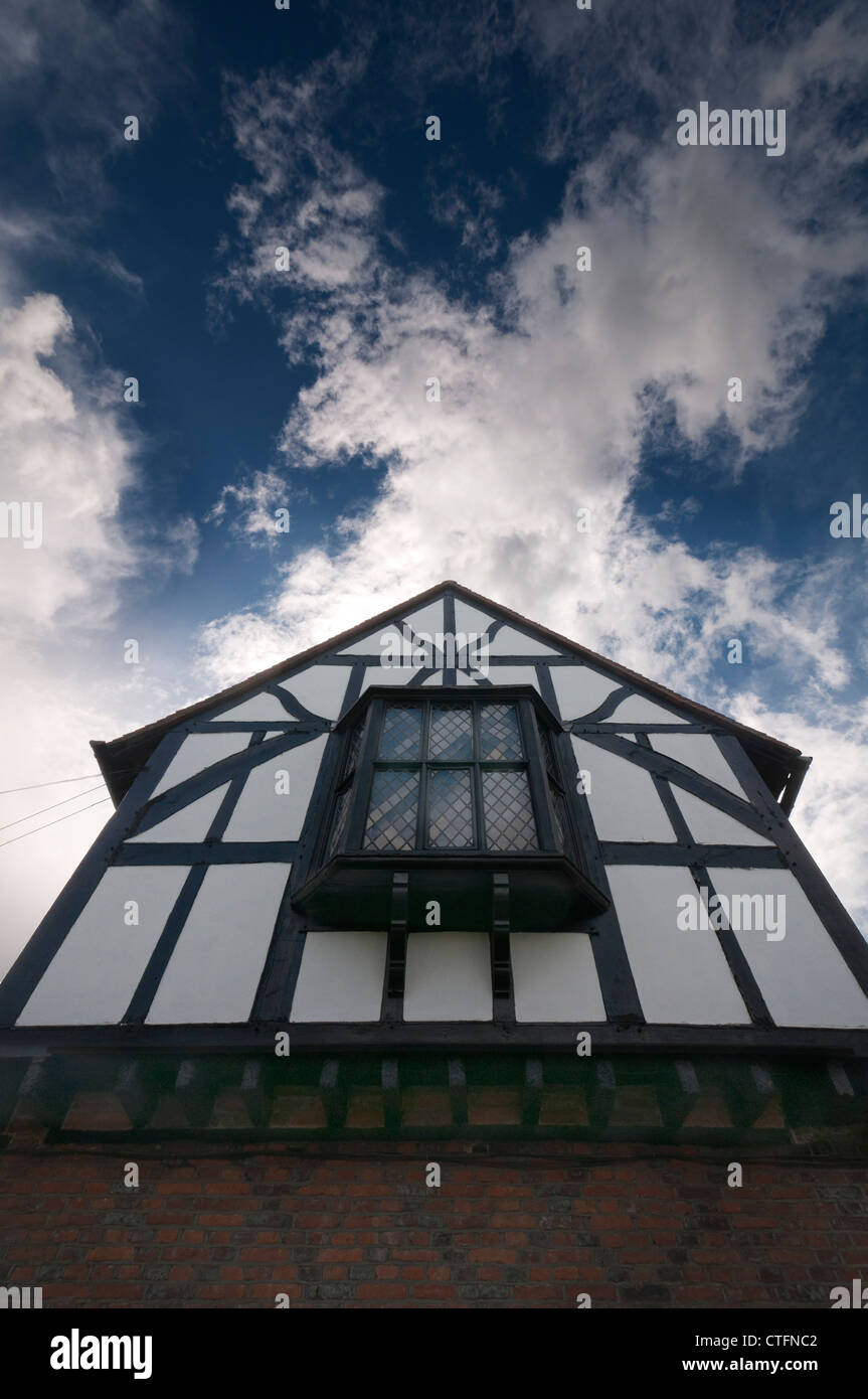 An upward view of a timber framed building and leaded window part of ...