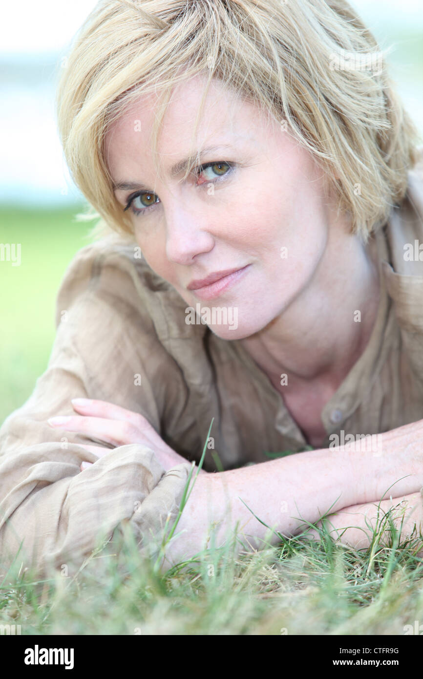 Concerned woman lying on grass Stock Photo - Alamy