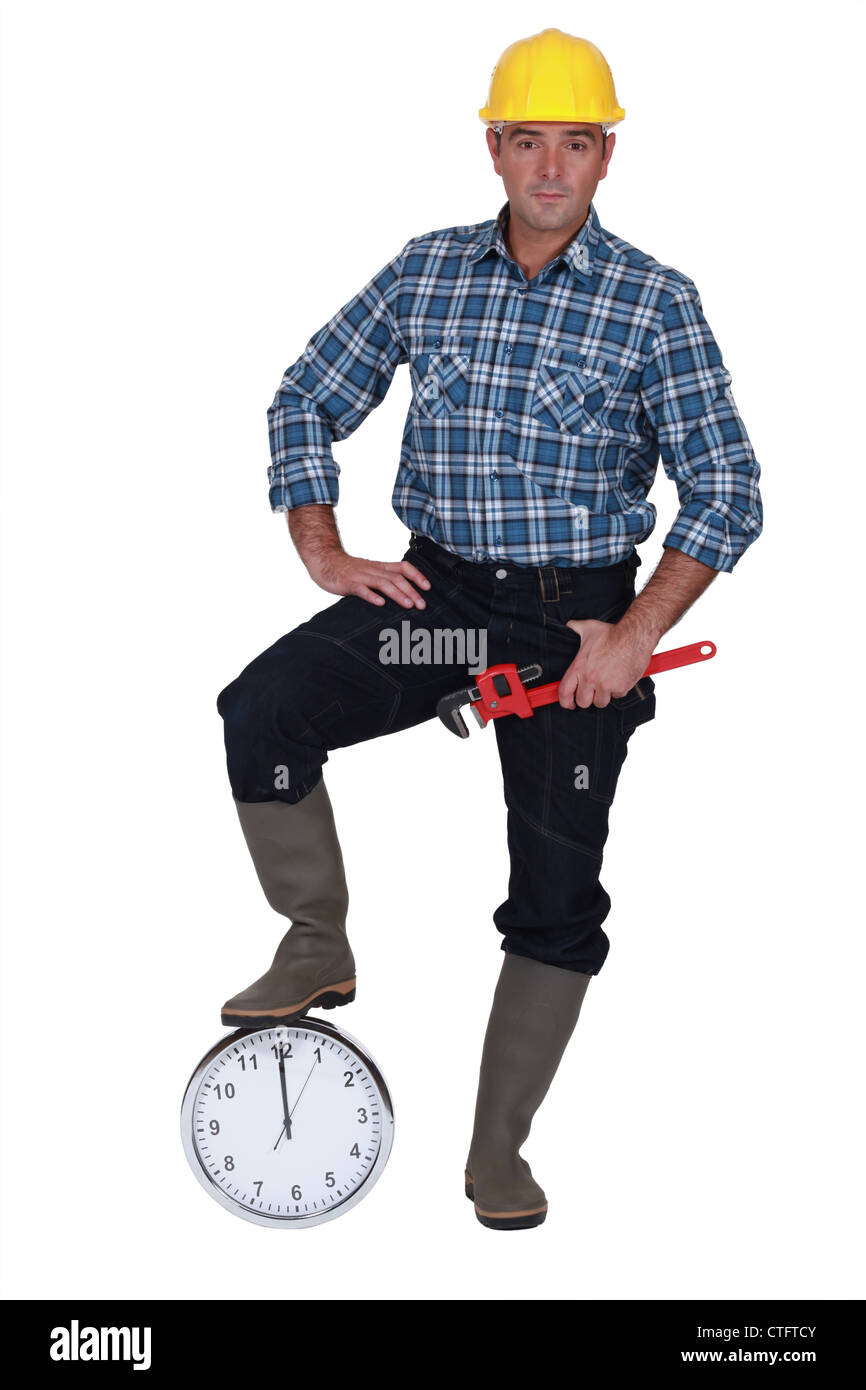 Builder resting foot on clock Stock Photo - Alamy