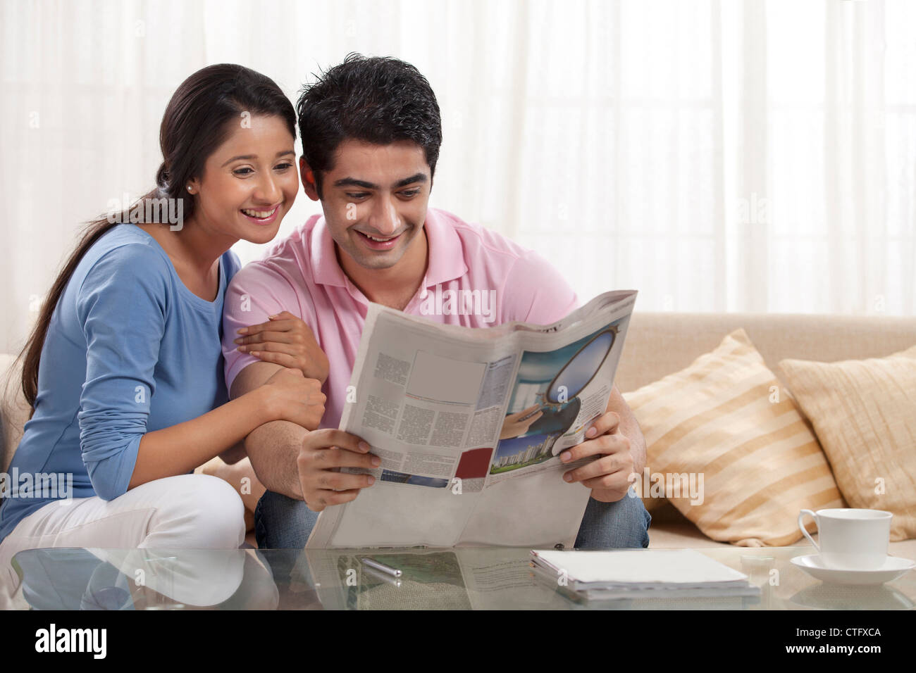 Young couple reading newspaper together at home Stock Photo - Alamy