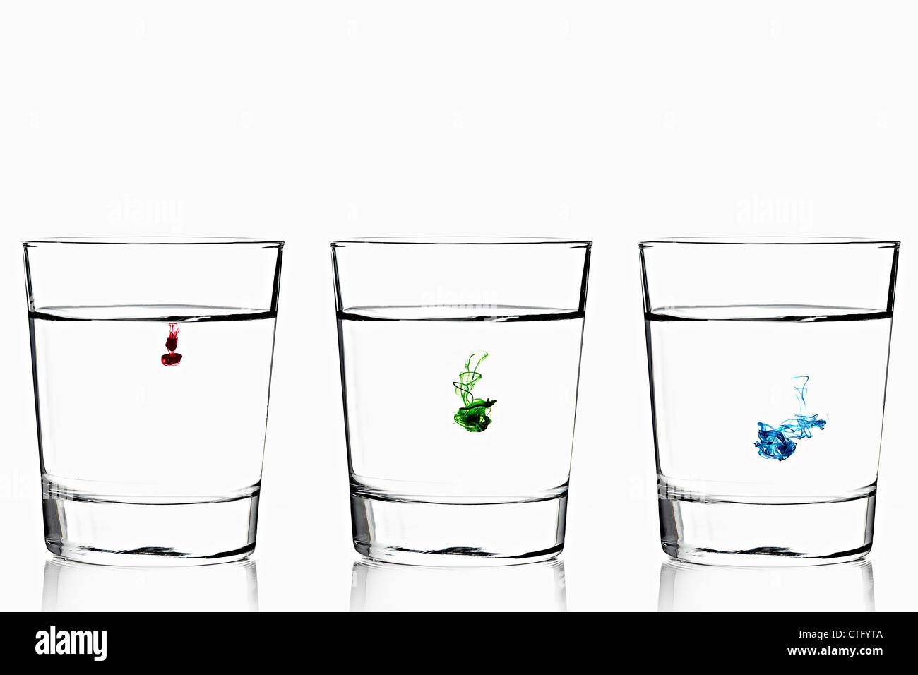 Red, green and blue food color diffusing into three glasses of water ...