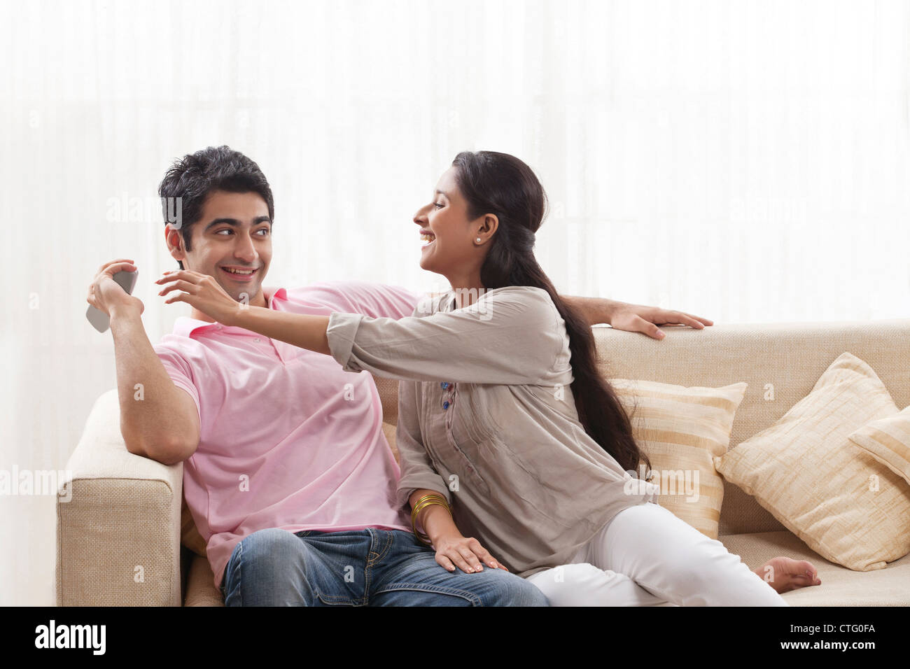Playful young man keeping remote control away from woman Stock Photo ...