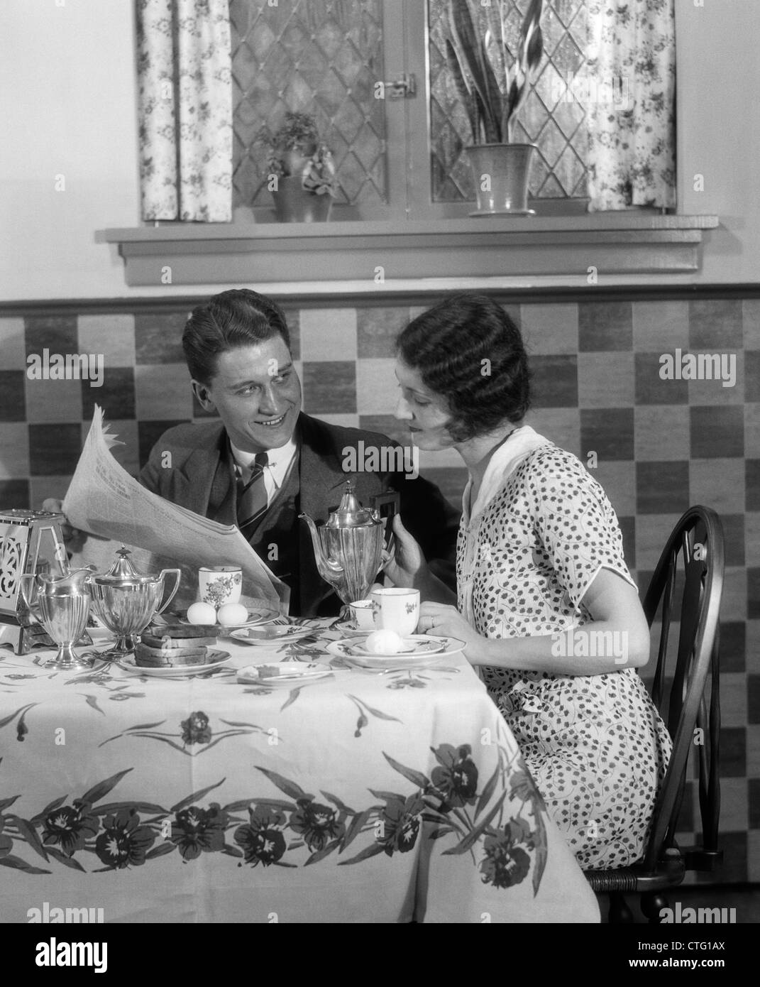 1920s 1930s COUPLE AT BREAKFAST TABLE LOOKING OVER NEWSPAPER WIFE ...