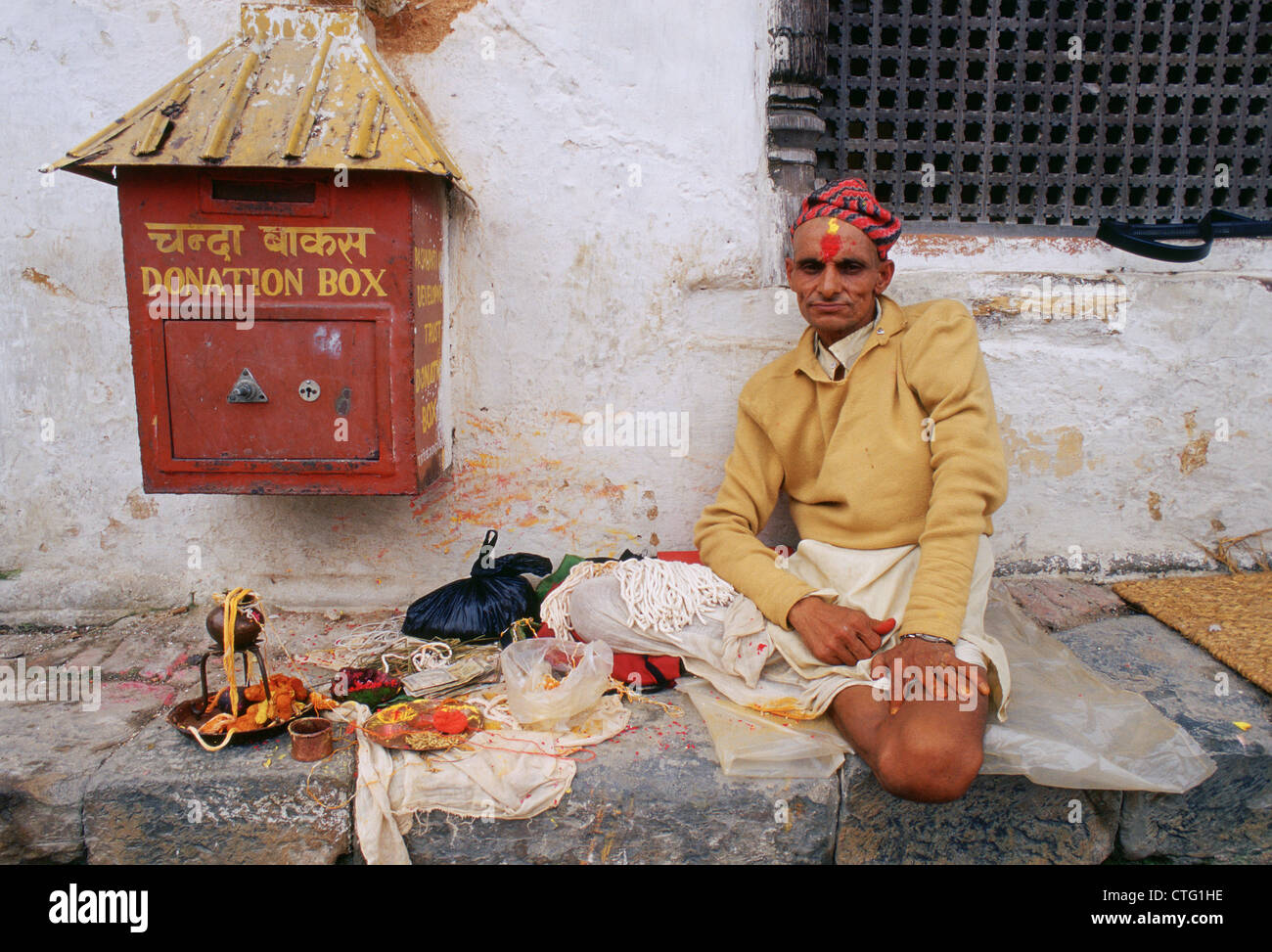 Hindu priest waiting for devotees to apply "tilak" ( red powder) on ...