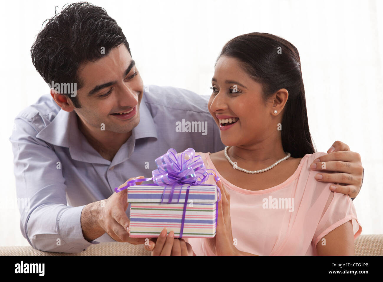 Handsome young man giving a gift to woman at home Stock Photo - Alamy