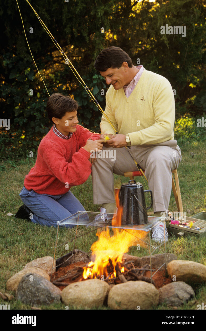 1990s FATHER AND SON BY CAMPFIRE WORKING ON FISHING ROD AND FLIES Stock ...