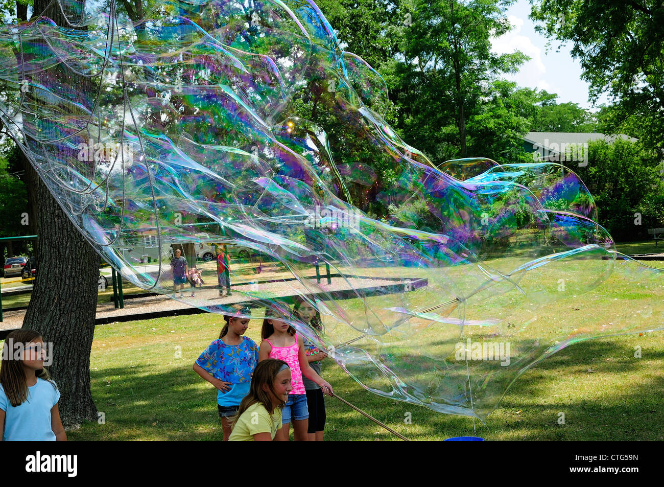 Kids blowing huge wind-blown bubbles at park festival Stock Photo - Alamy