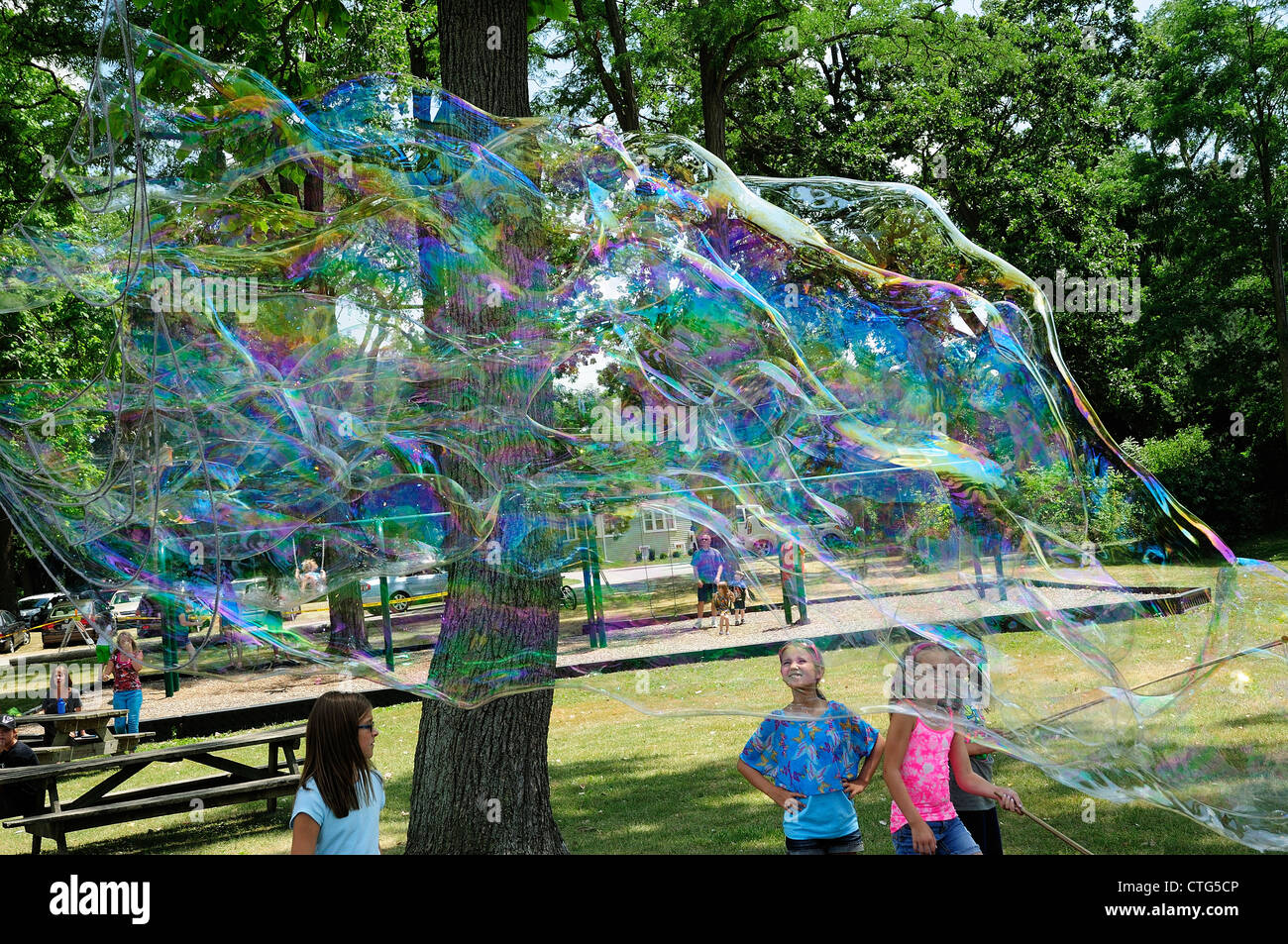 Kids blowing huge wind-blown bubbles at park festival Stock Photo - Alamy