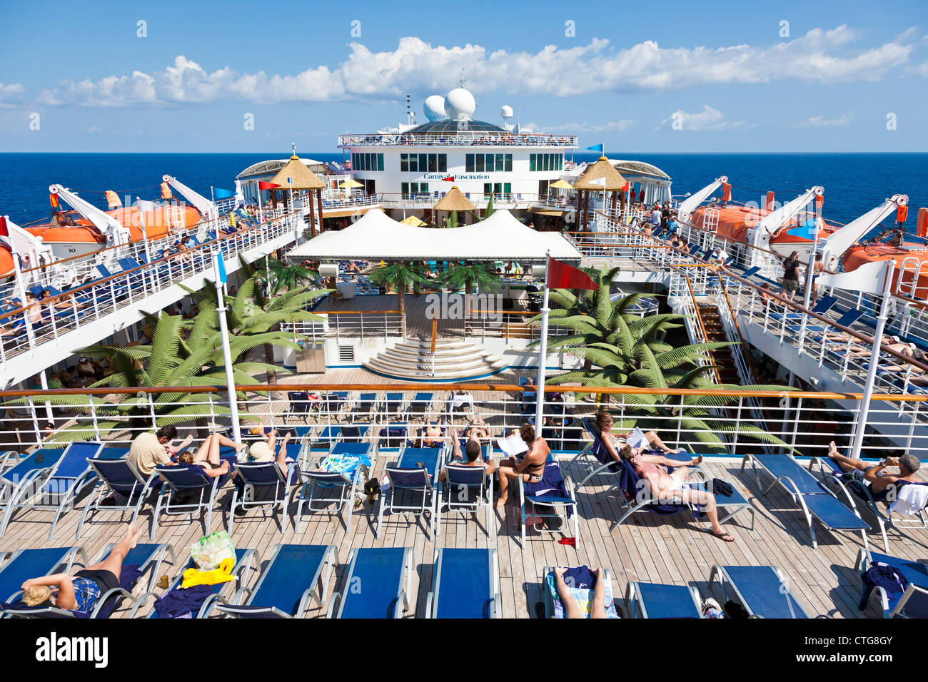 Cruise passengers enjoying the sun on decks of Carnival Fascination ...