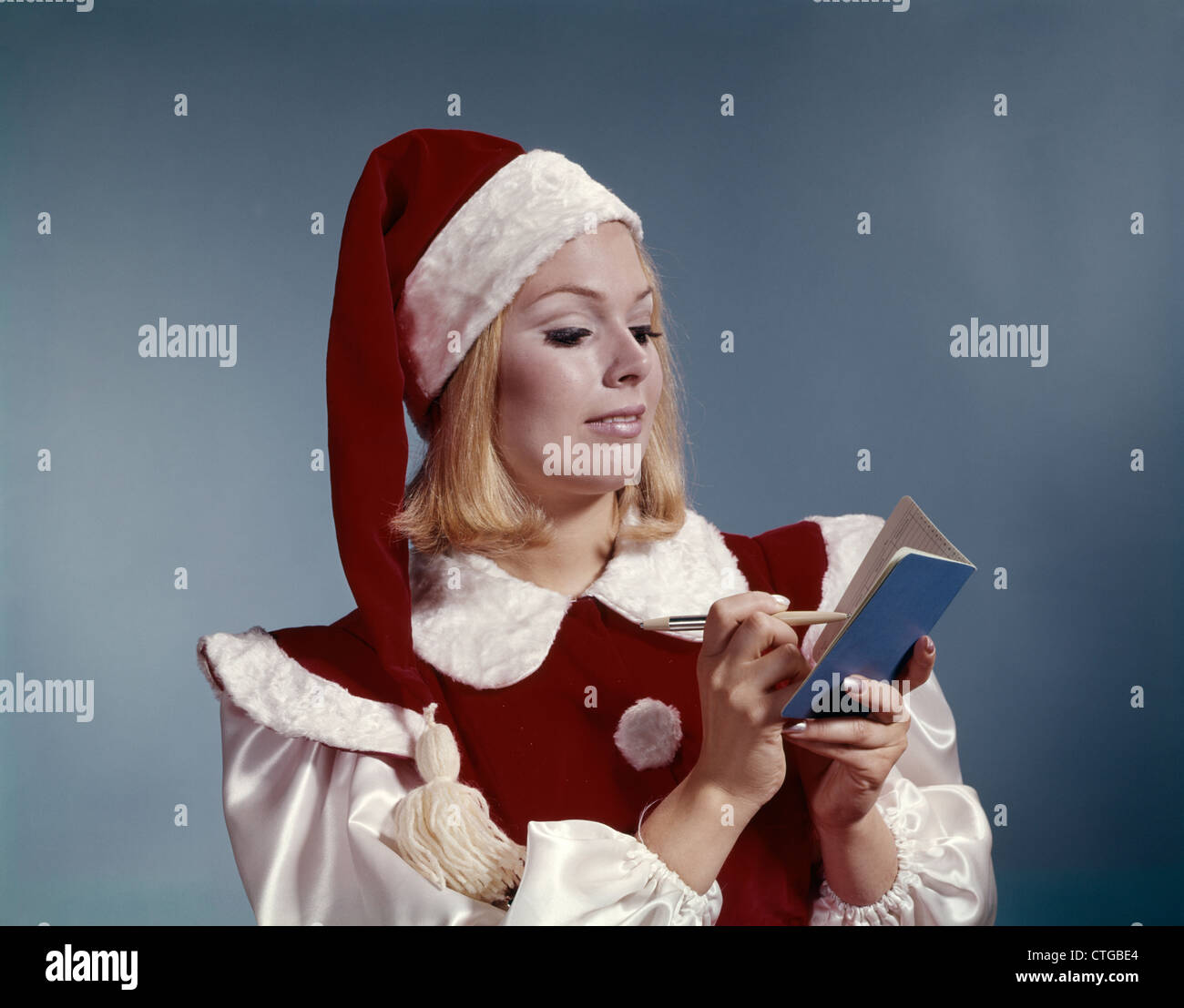 1960s WOMAN CHRISTMAS SANTA HELPER COSTUME PORTRAIT SMILING WRITING ...
