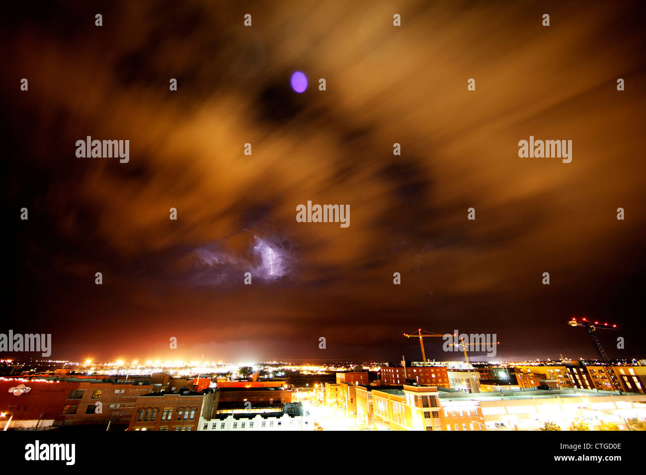 Clouds streak above a city center as lightning strikes behind in a long ...